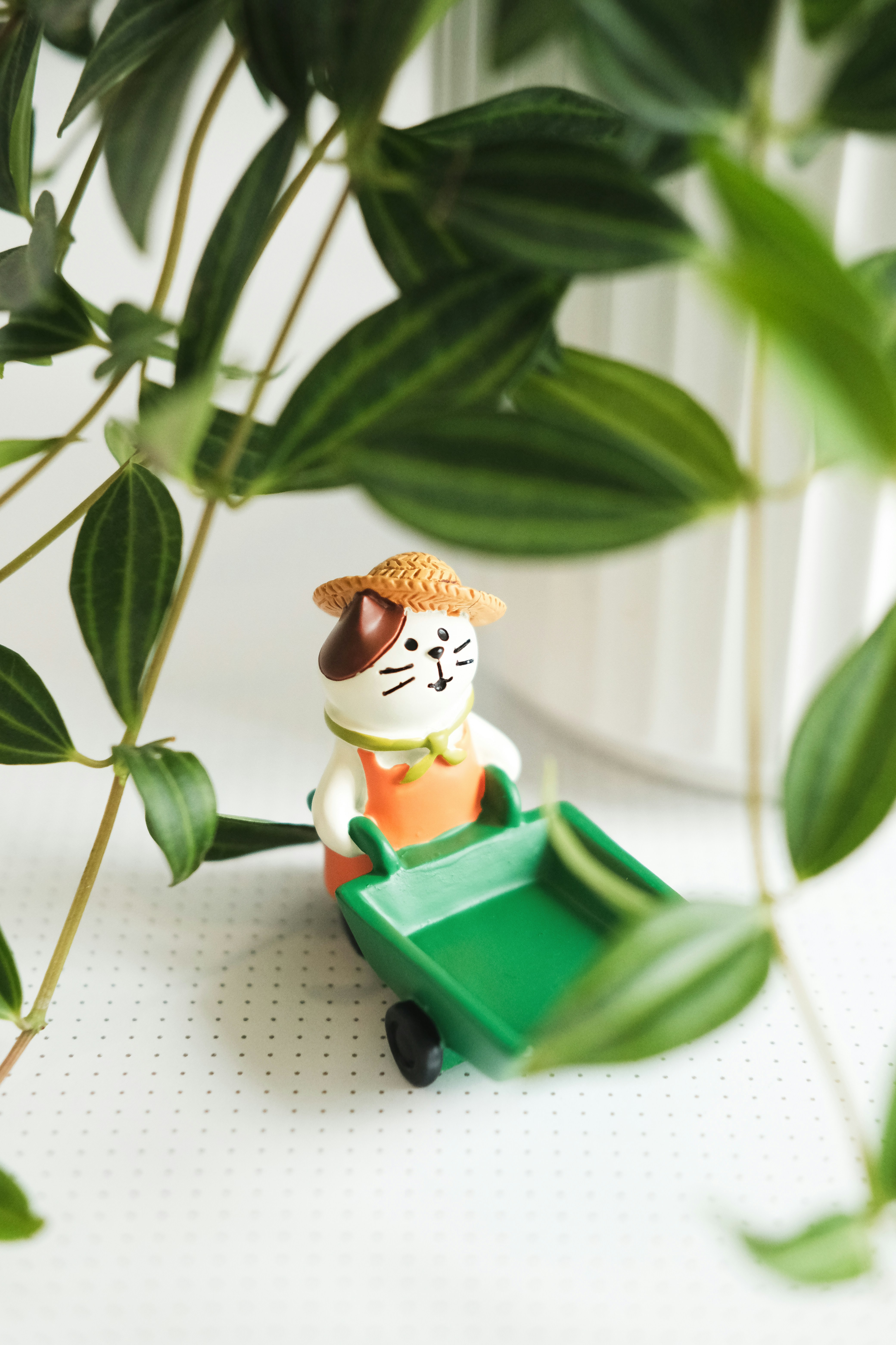 Whimsical Toy Cat Circulates Green Wheels Among Hanging Leaves