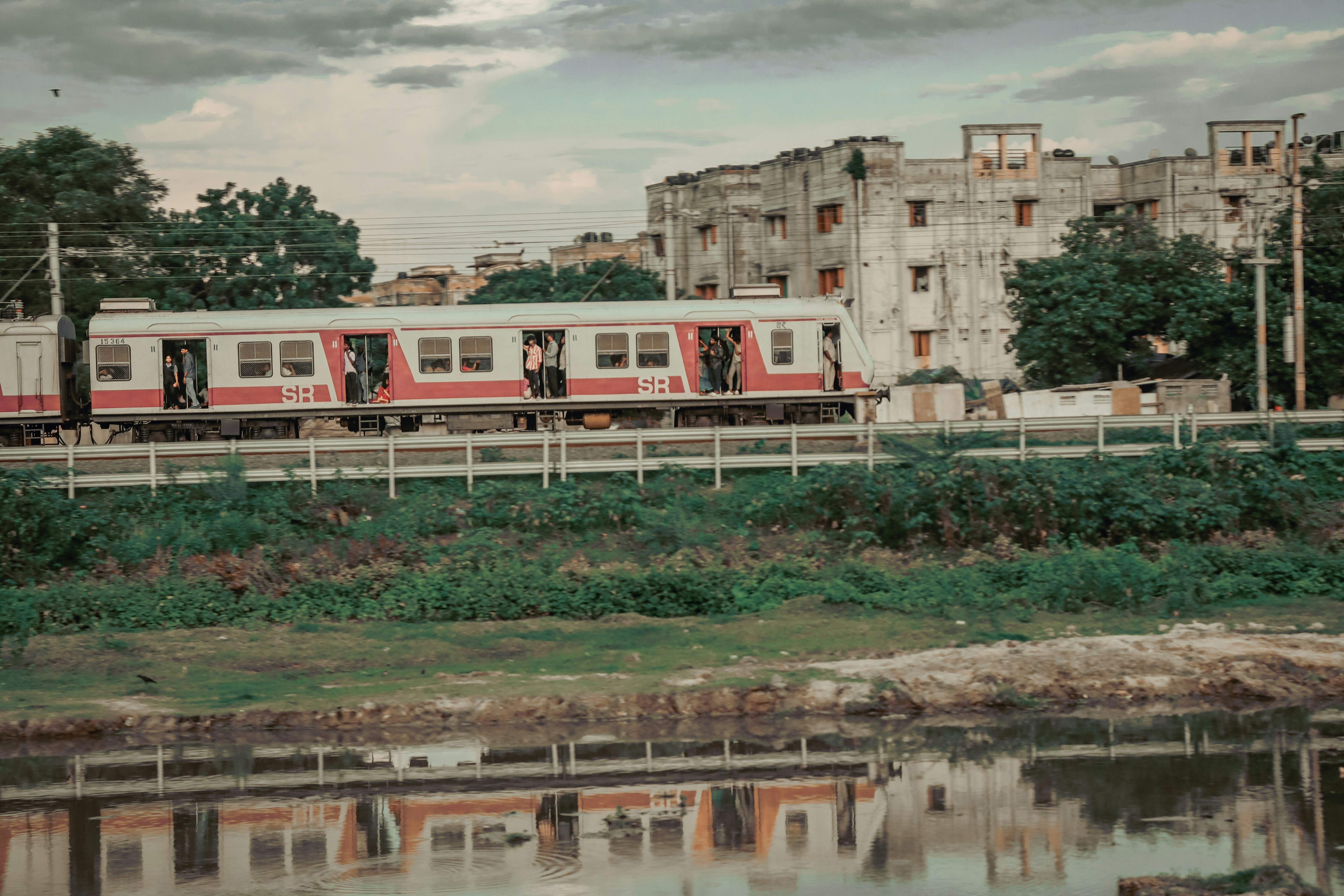 A train traveling down tracks next to a body of water photo – Free ...