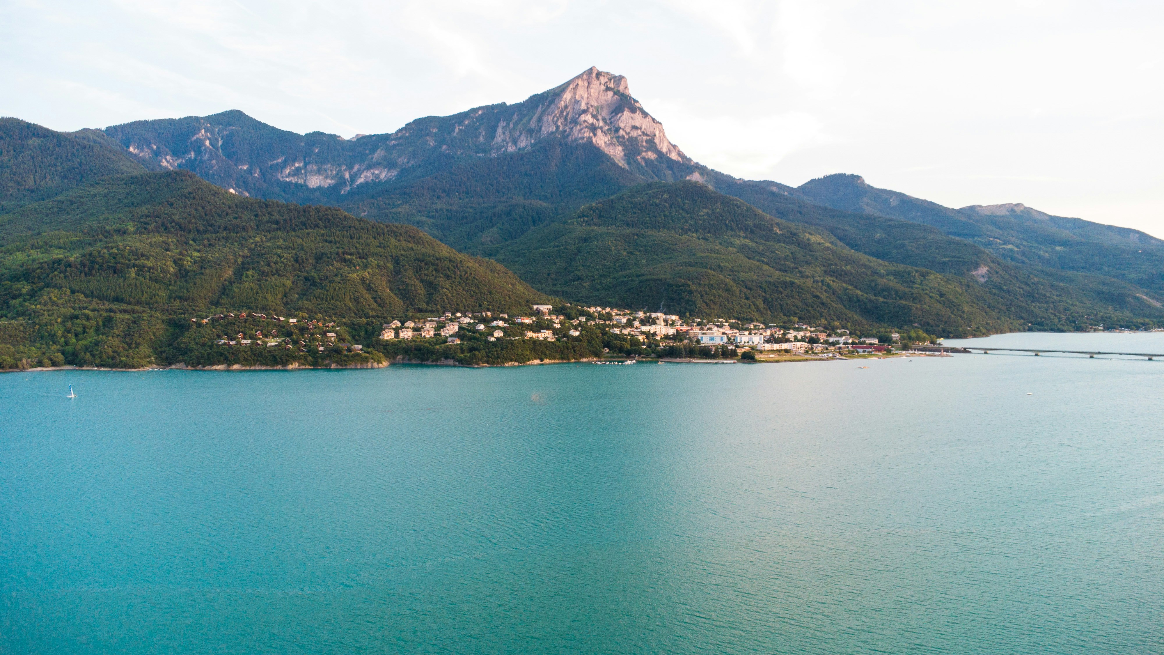 Expansive turquoise lake bordered by lush mountains and a quaint village.