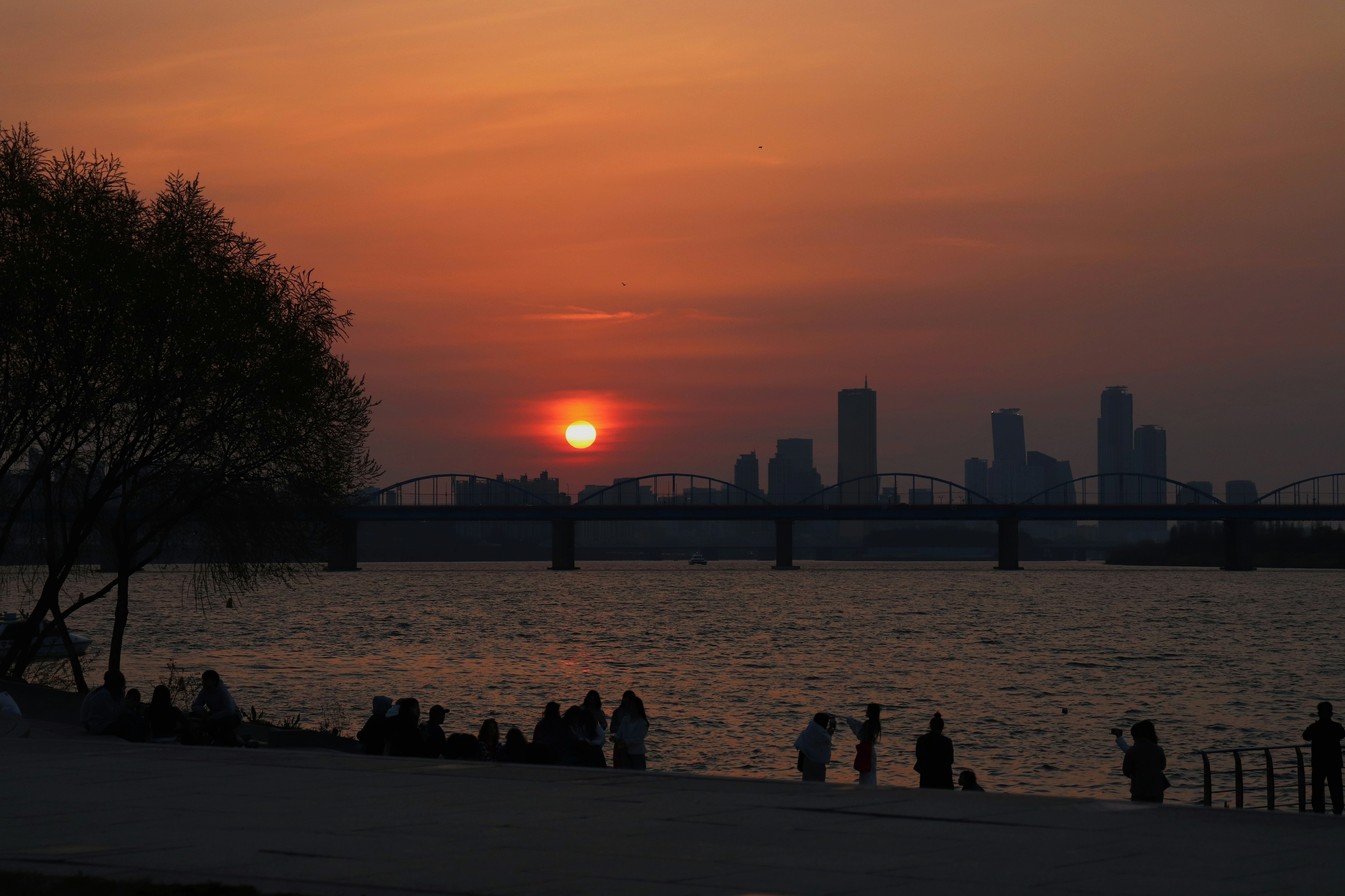 Sunset Over the River: Silhouetted Cityscape and Pier