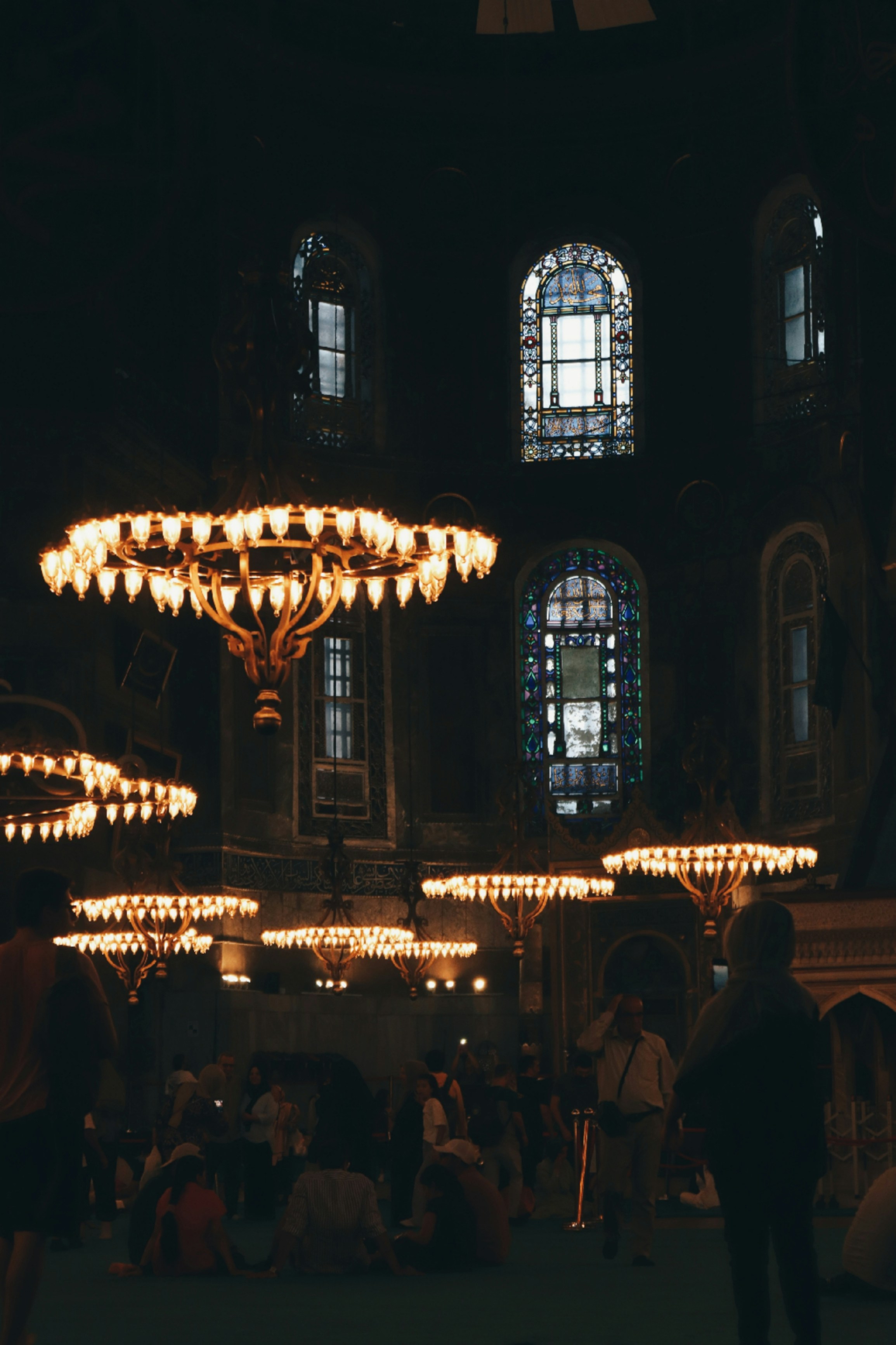 A group of people standing around a room with chandeliers photo – Free ...