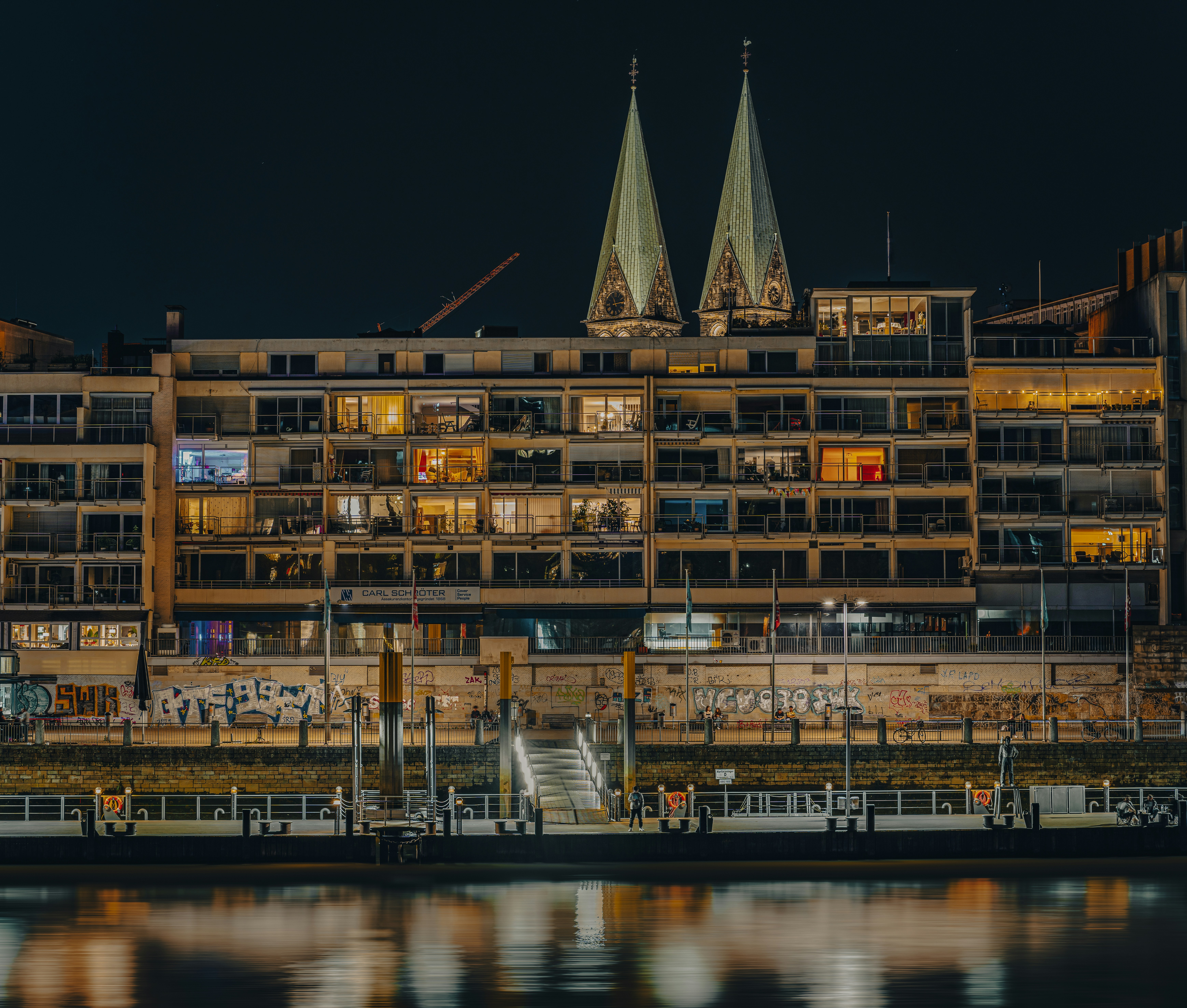 Twin Spires Over the Riverside: Nighttime Facade with Warm Windows