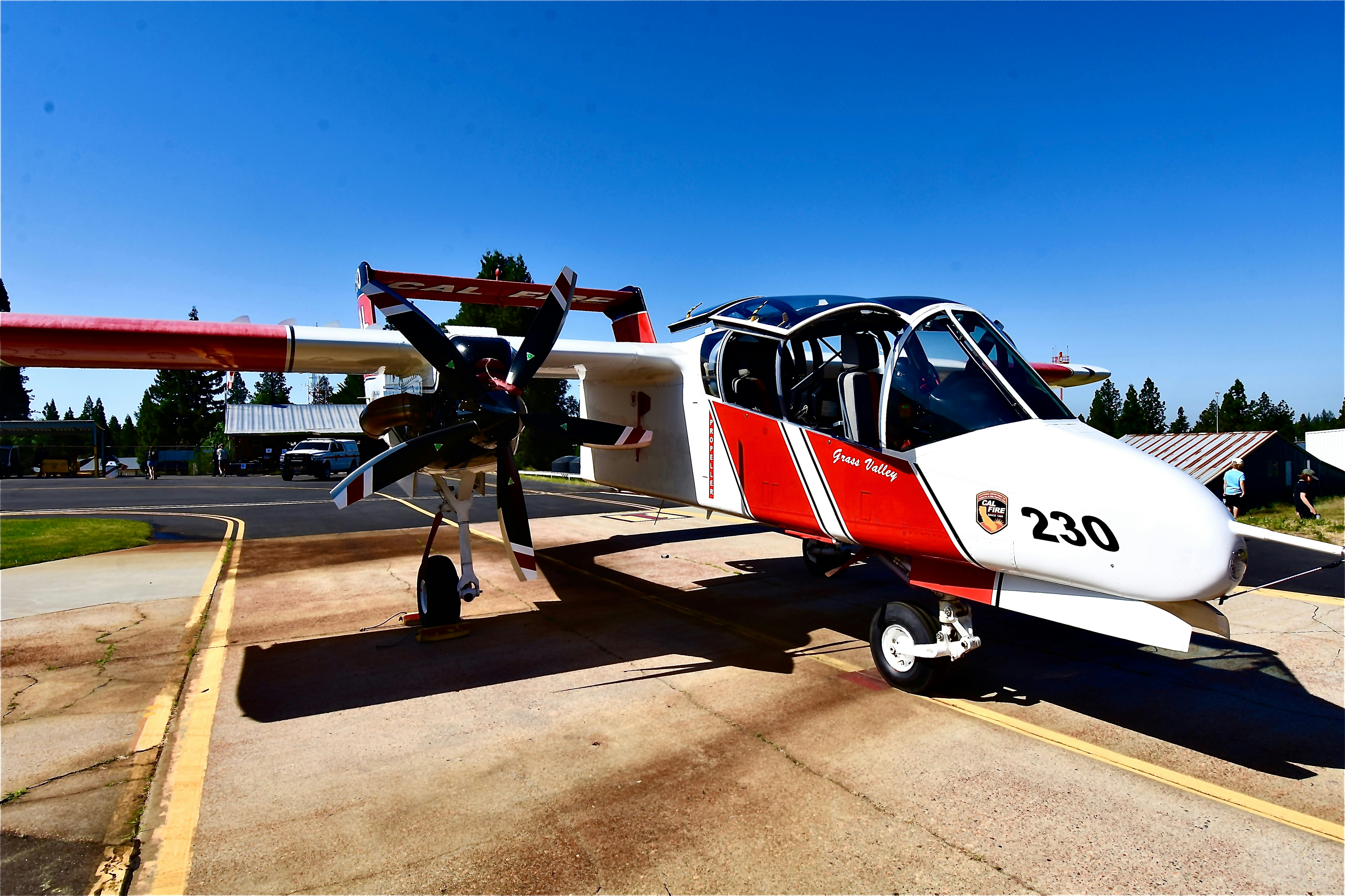 Firefighting aircraft parked on the tarmac, showcasing its vibrant red and white design under a clear blue sky.