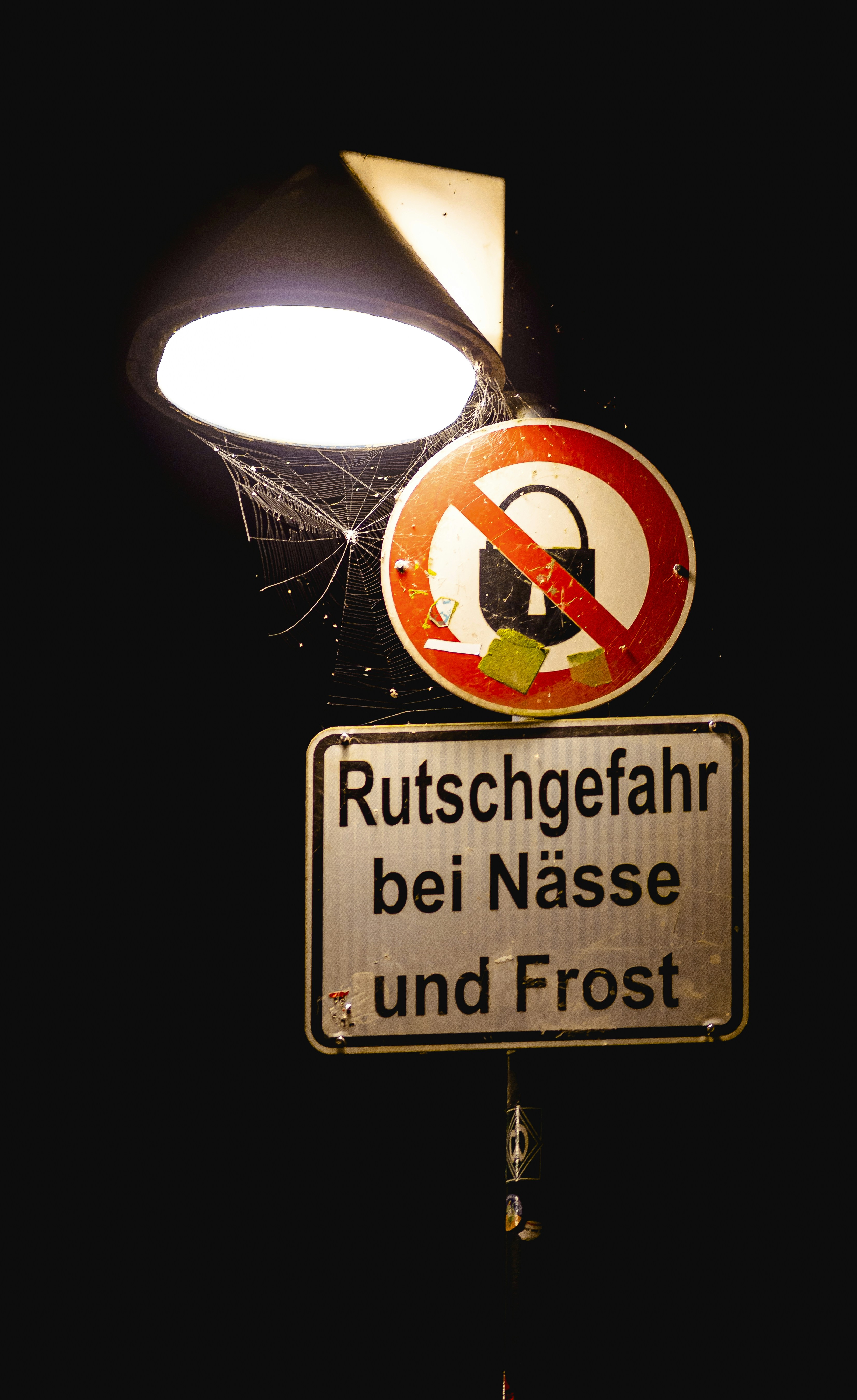 No-Entry Halo: Night Streetlamp Illuminates a Weathered German Warning Sign