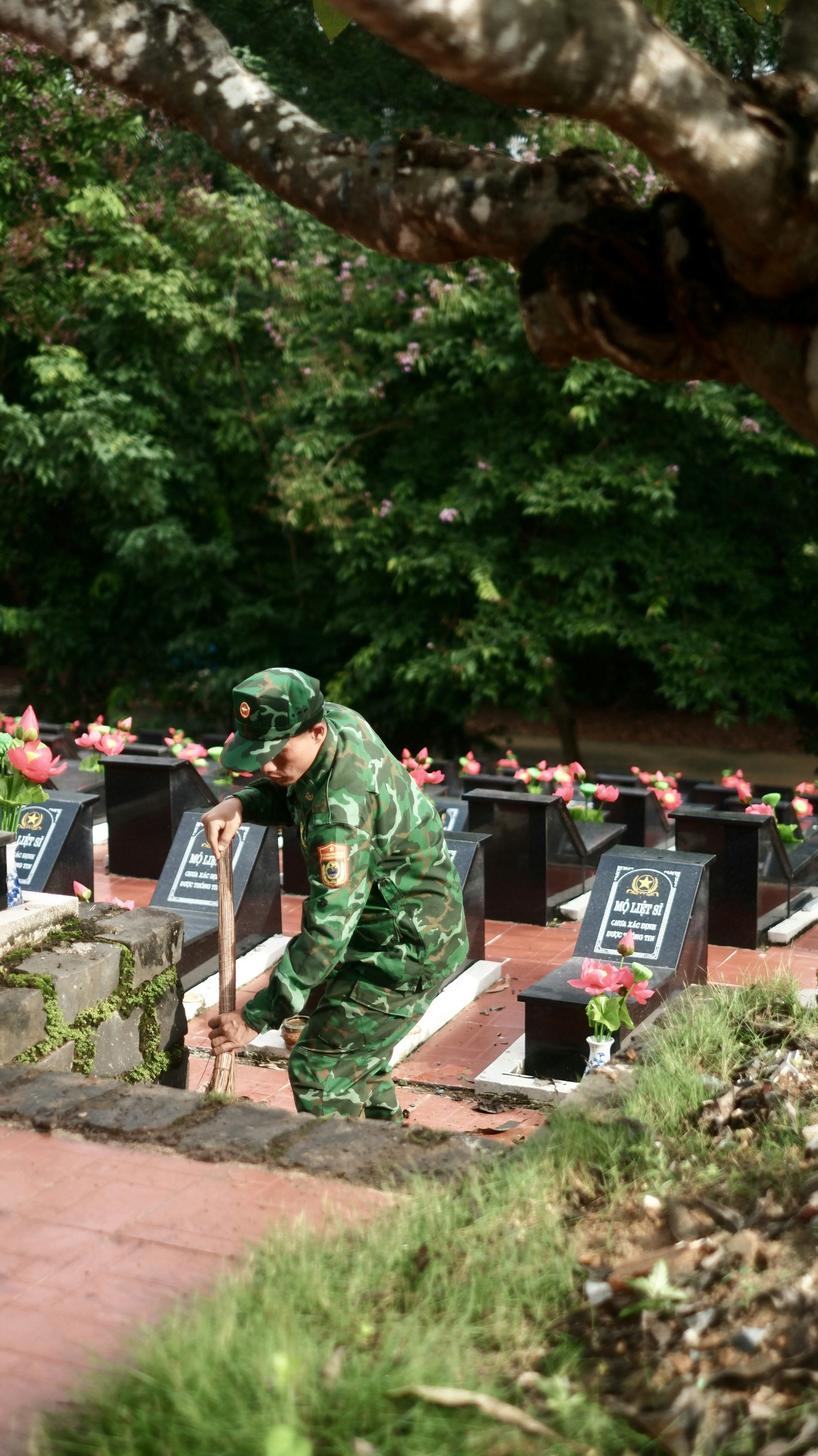 A man in a green uniform standing in front of a cemetery photo – Free ...