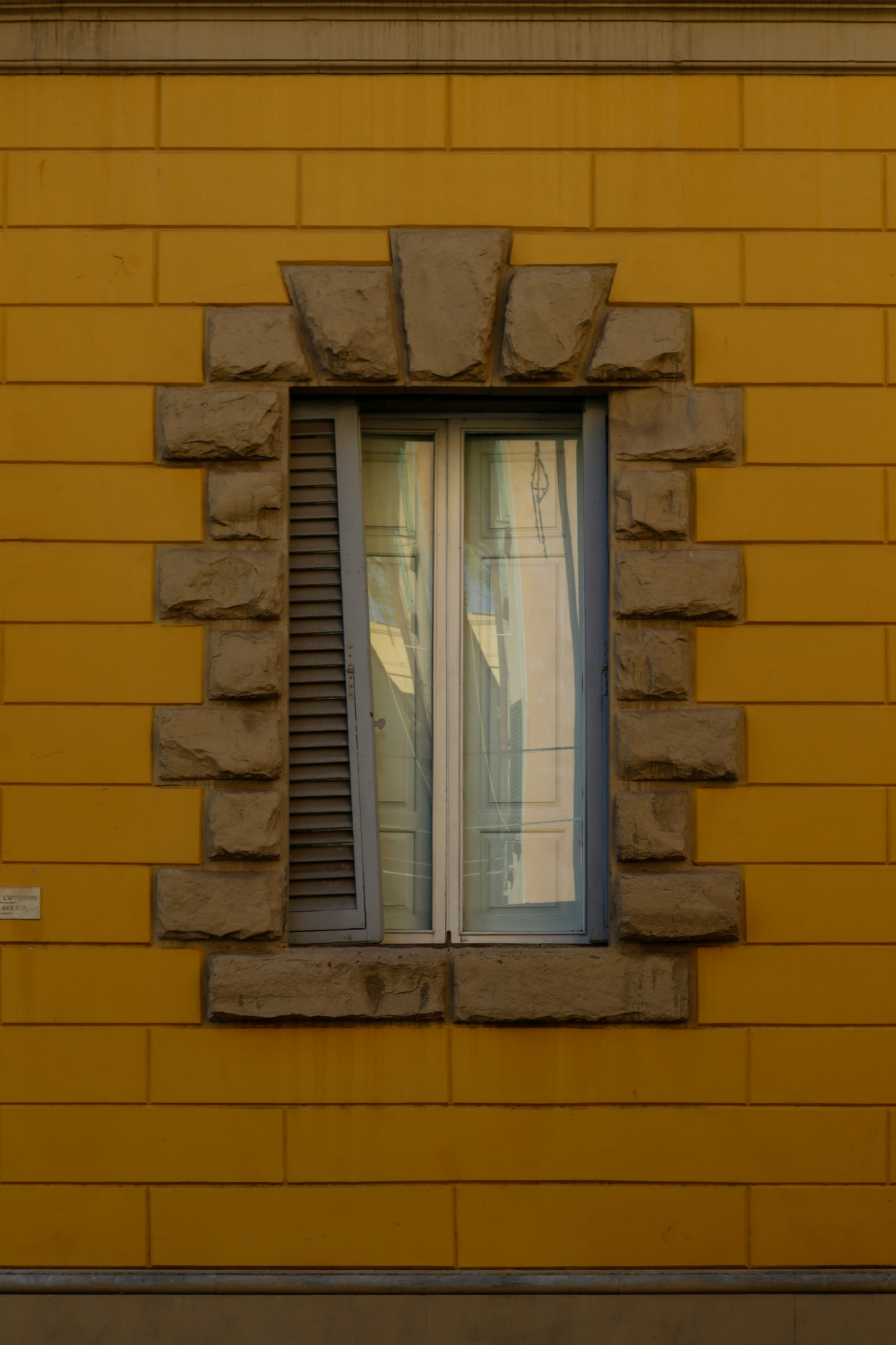 Golden Frame: A Window Centered in a Sunlit Yellow Facade