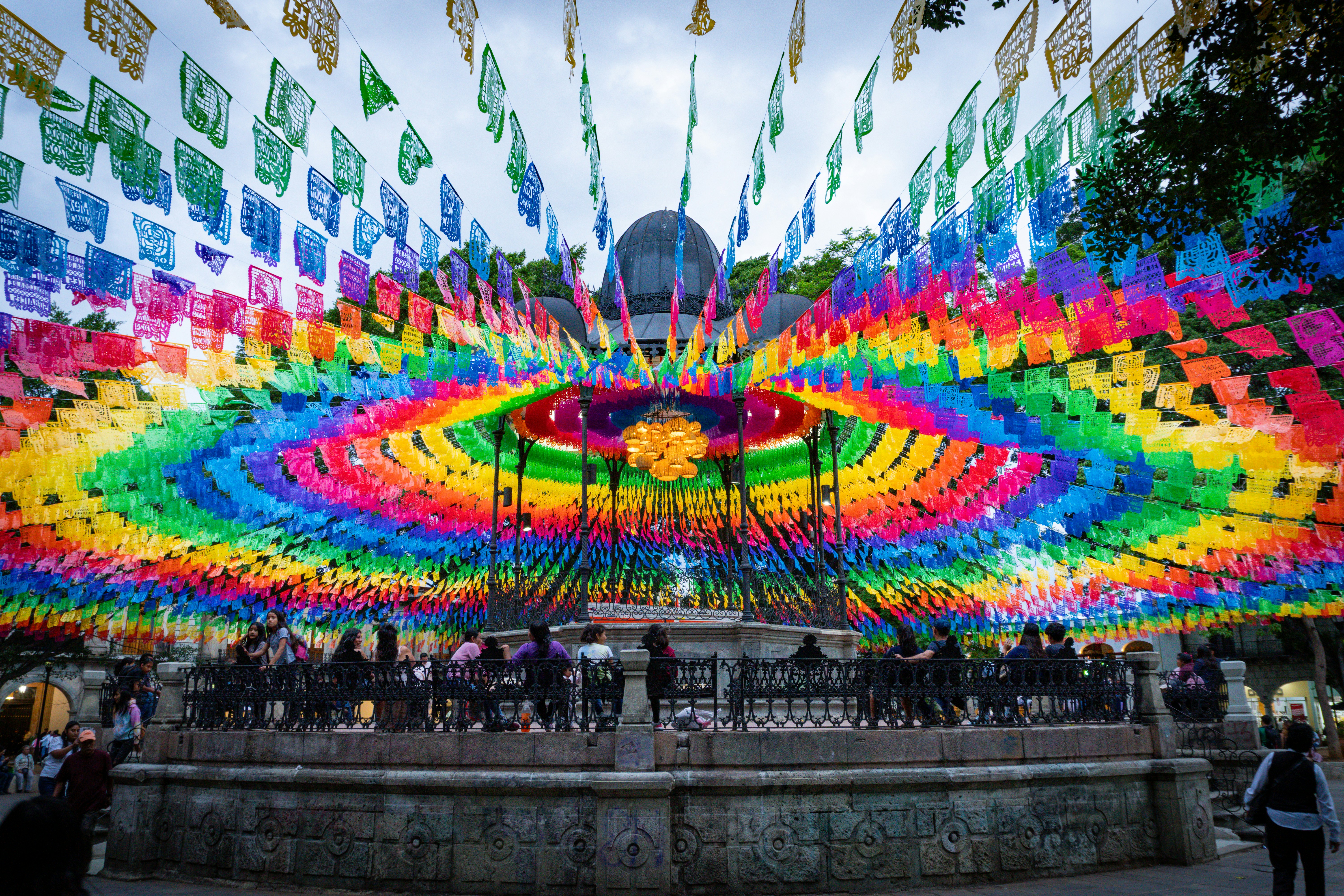 A large multicolored display of flags in front of a building photo ...