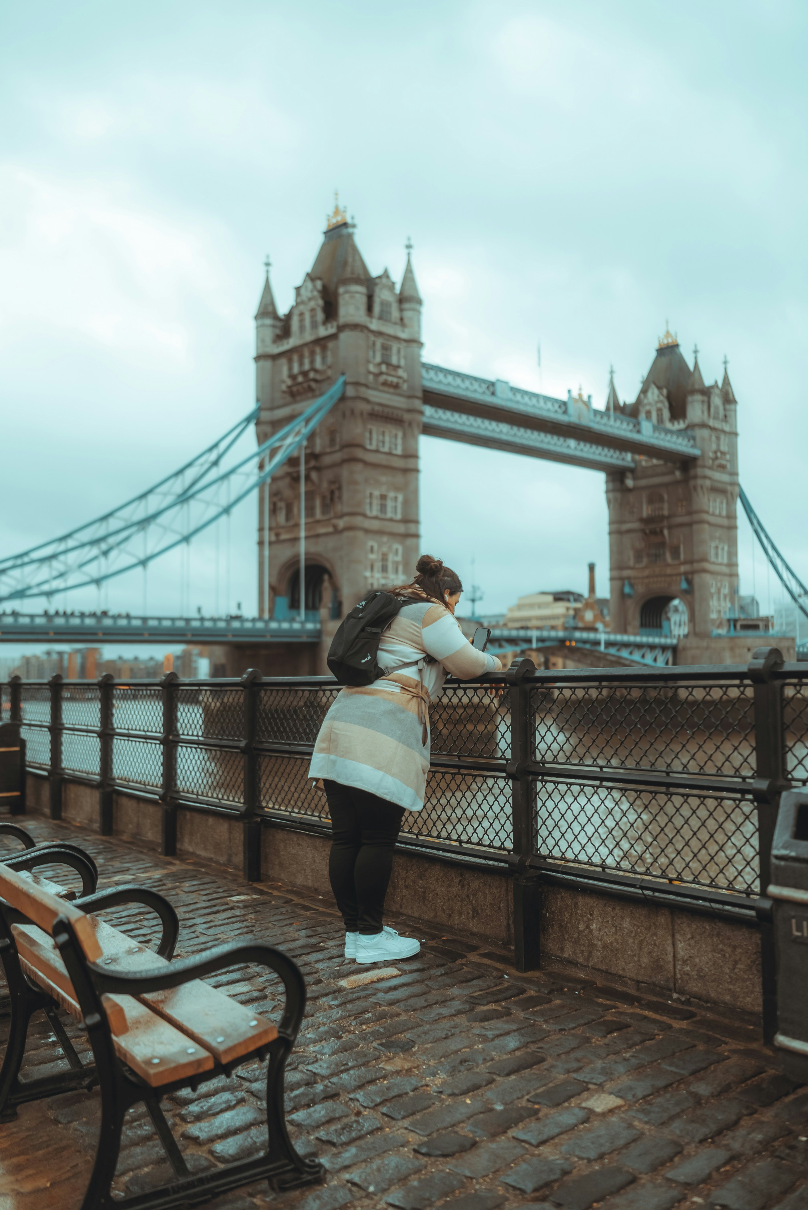 A woman standing on a bridge next to benches photo – Free Street ...