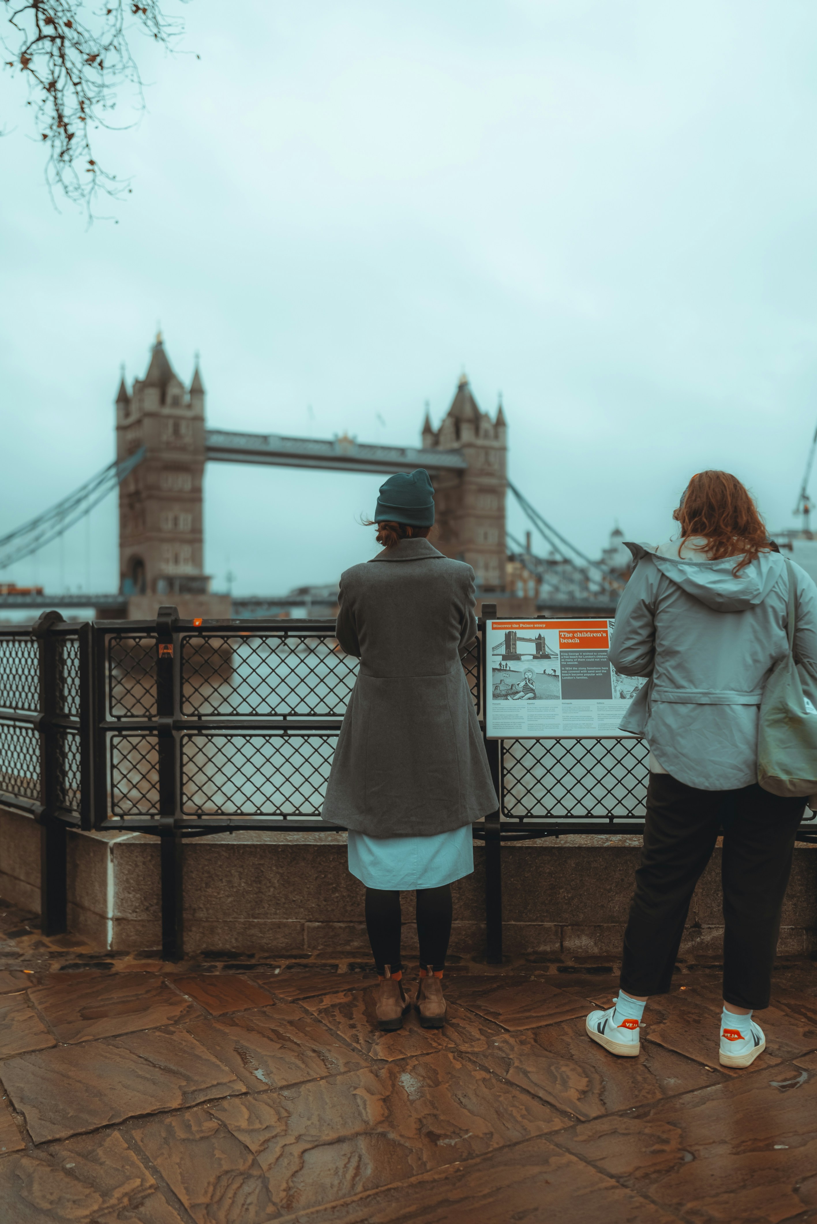 Two people standing on a bridge looking at the water photo – Free ...