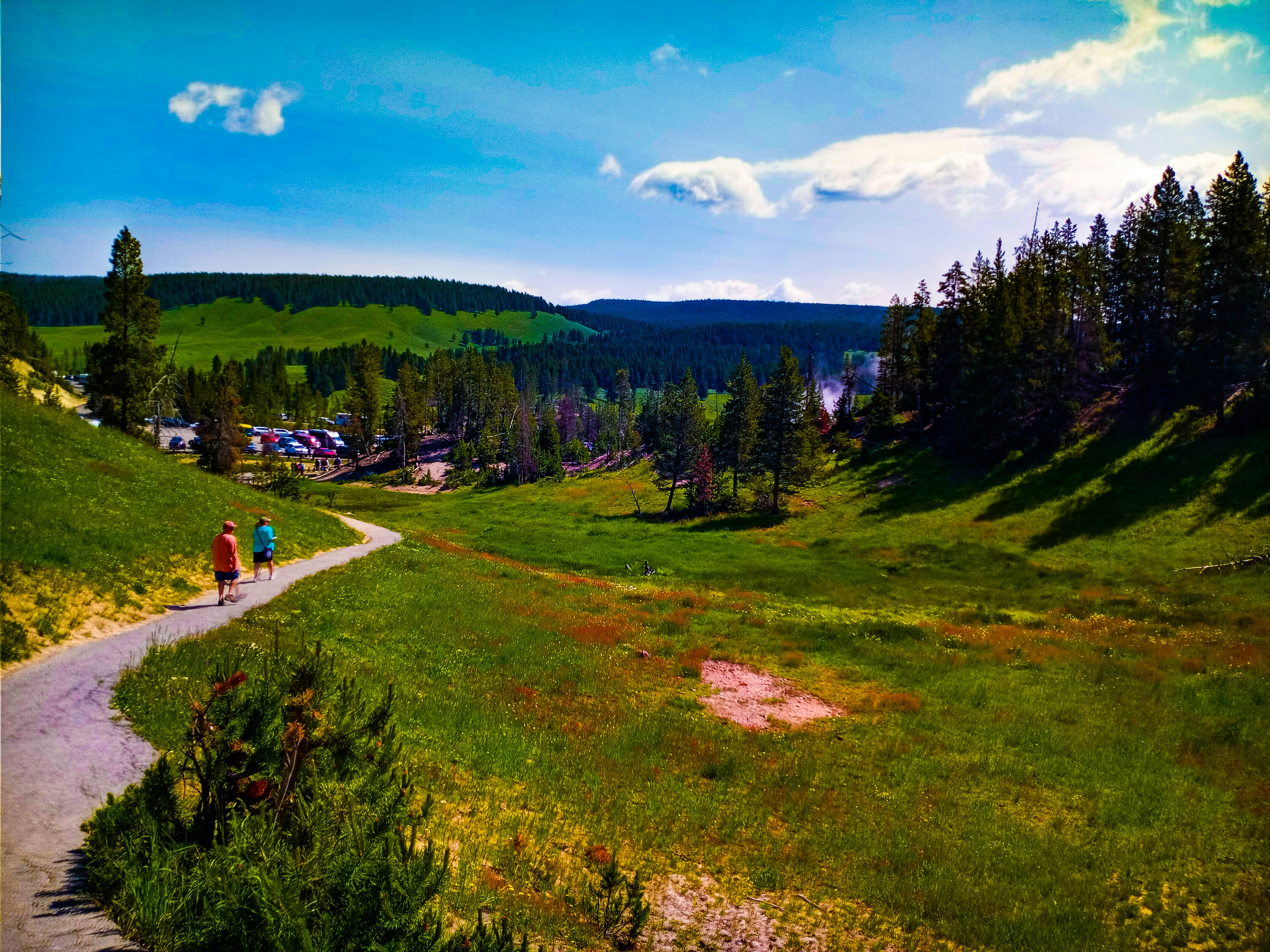 A couple of people walking down a dirt road