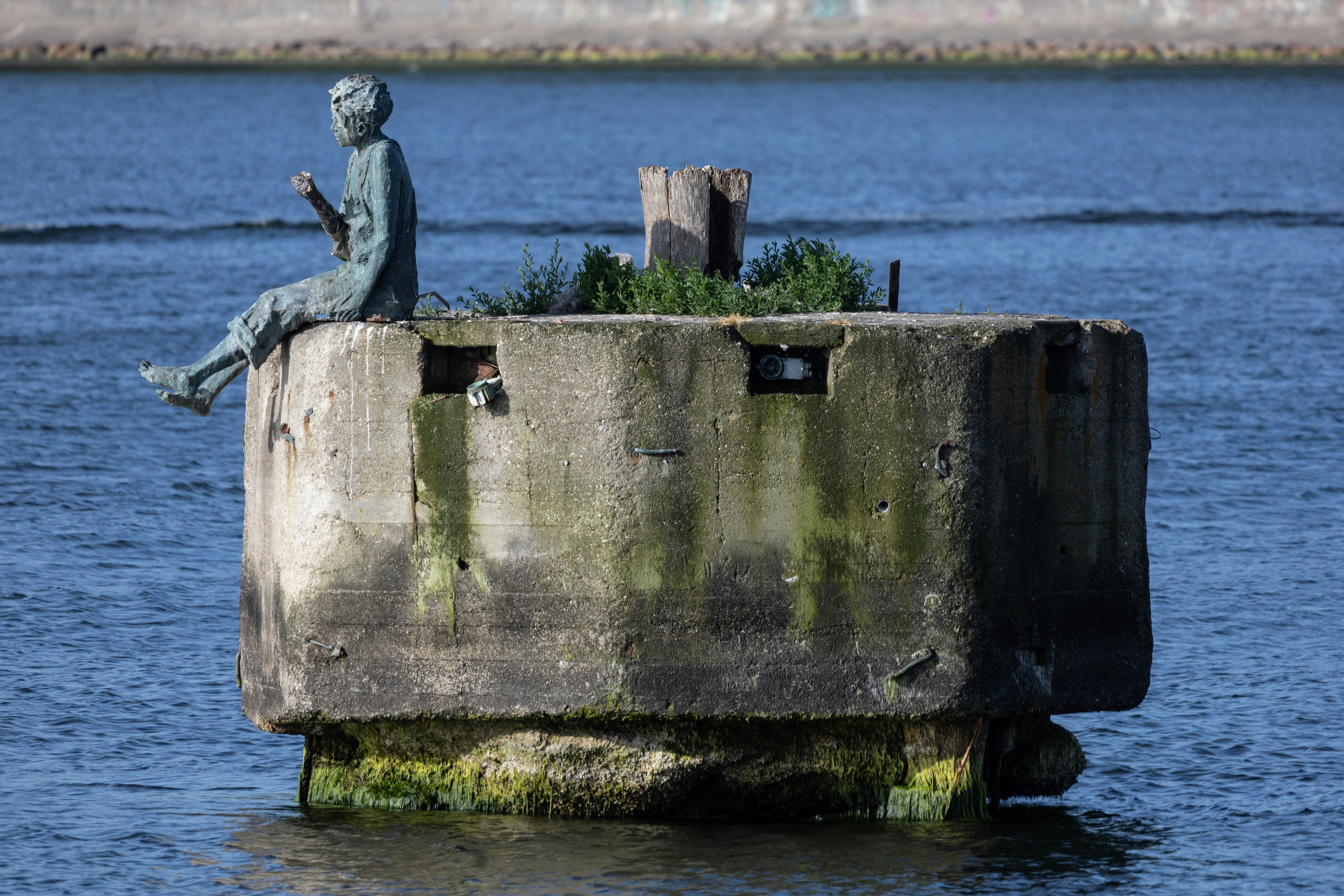 Sea-Sentinel: A Bronze Figure Perched on a Weathered Concrete Barque