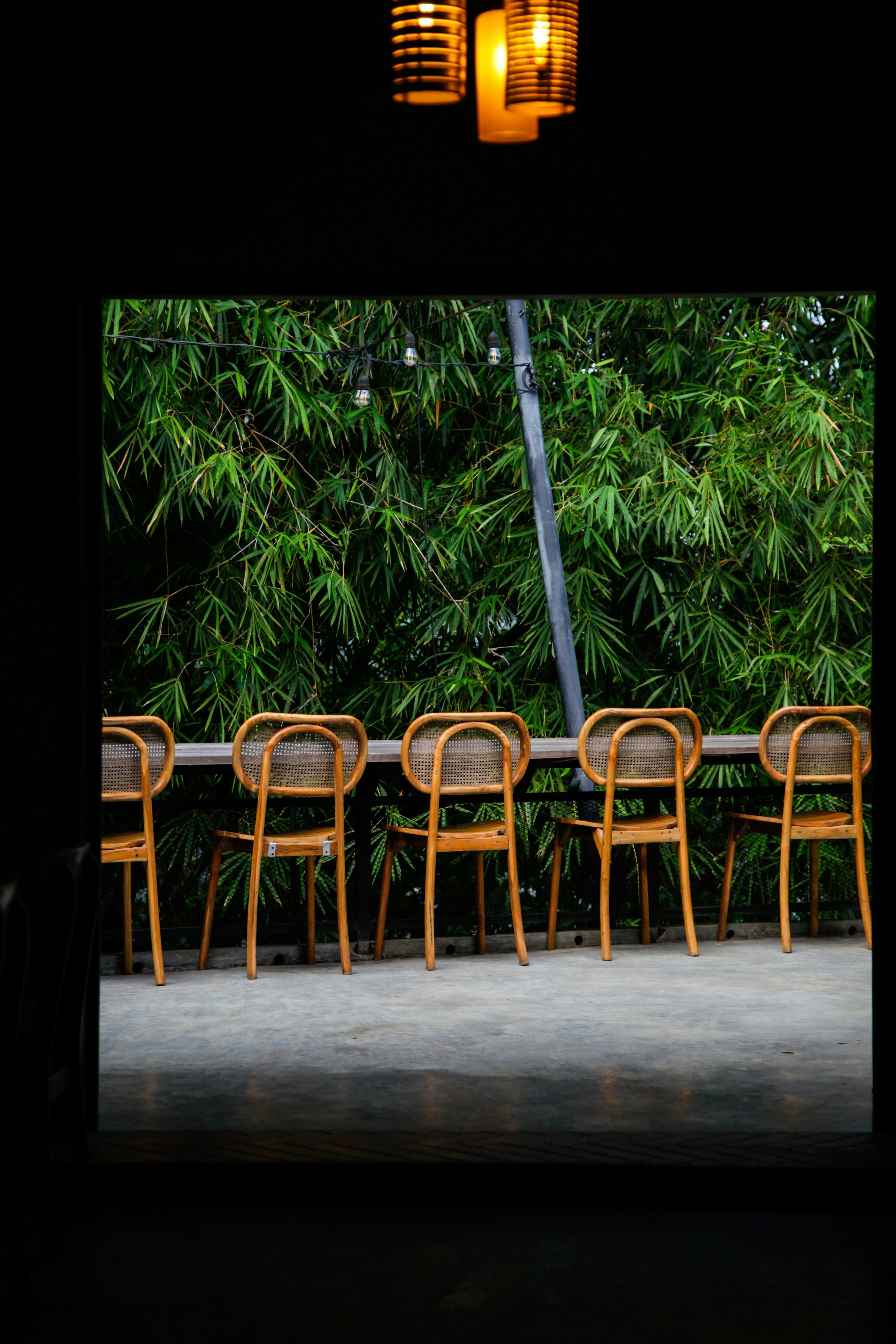 Row of Bamboo Lounge Chairs Framed by Night-Illuminated Balcony Atrium