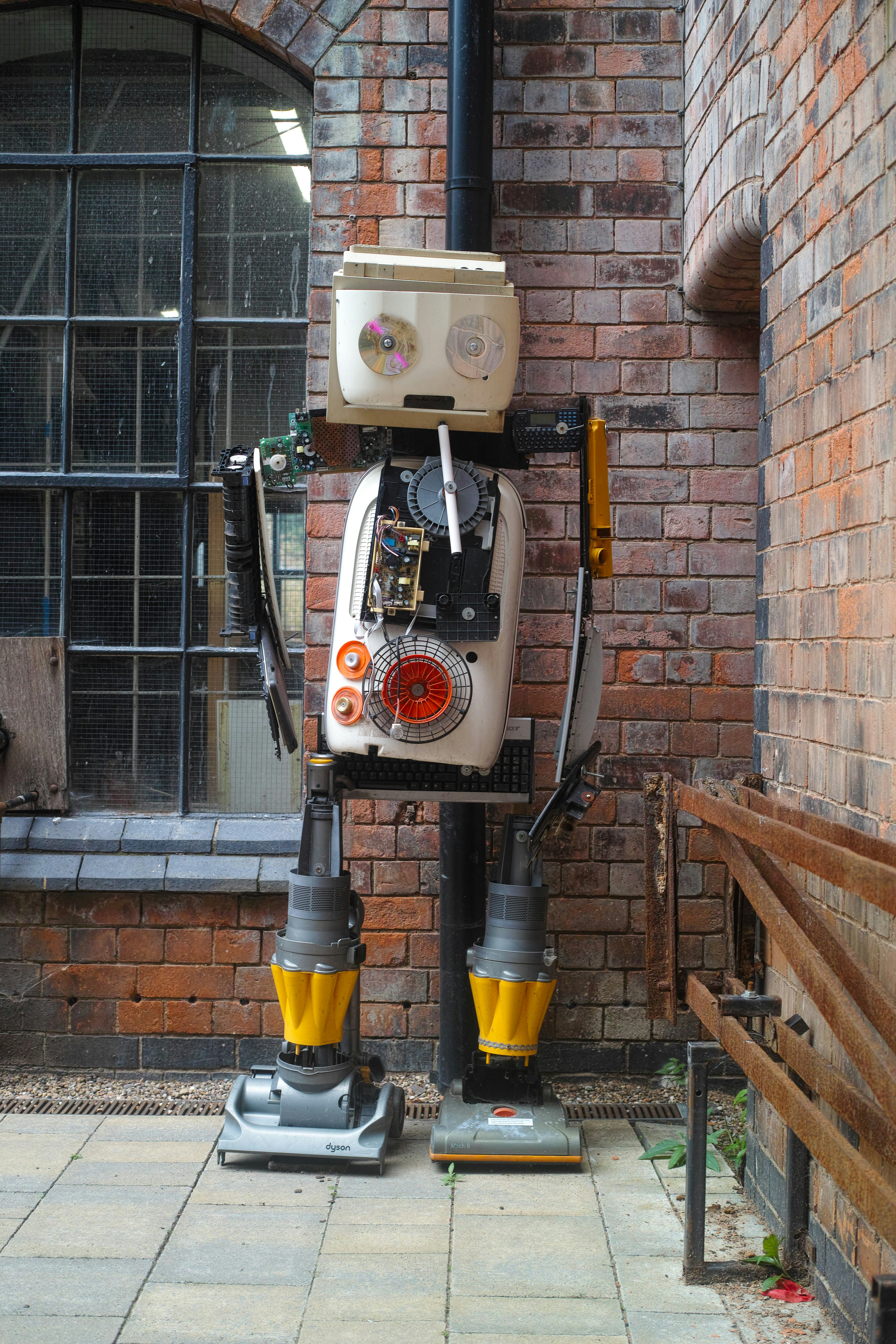 A robot standing in front of a brick building photo – Free Brick Image ...