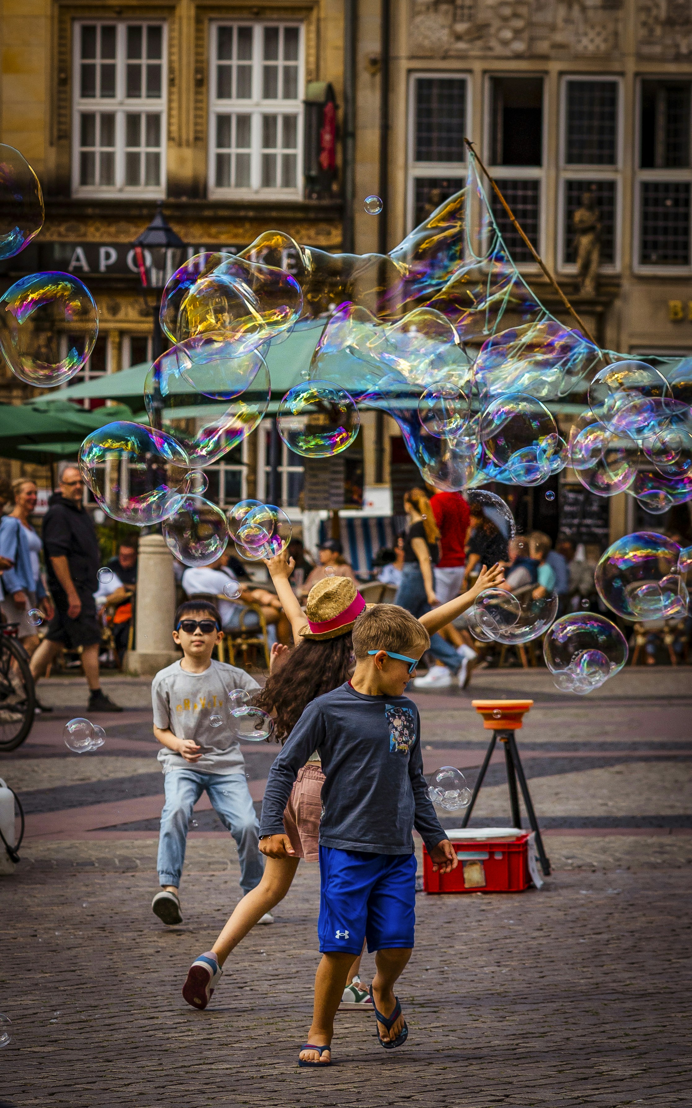 Bubble Ballet in the City Square: Children Chasing Iridescent Orbs
