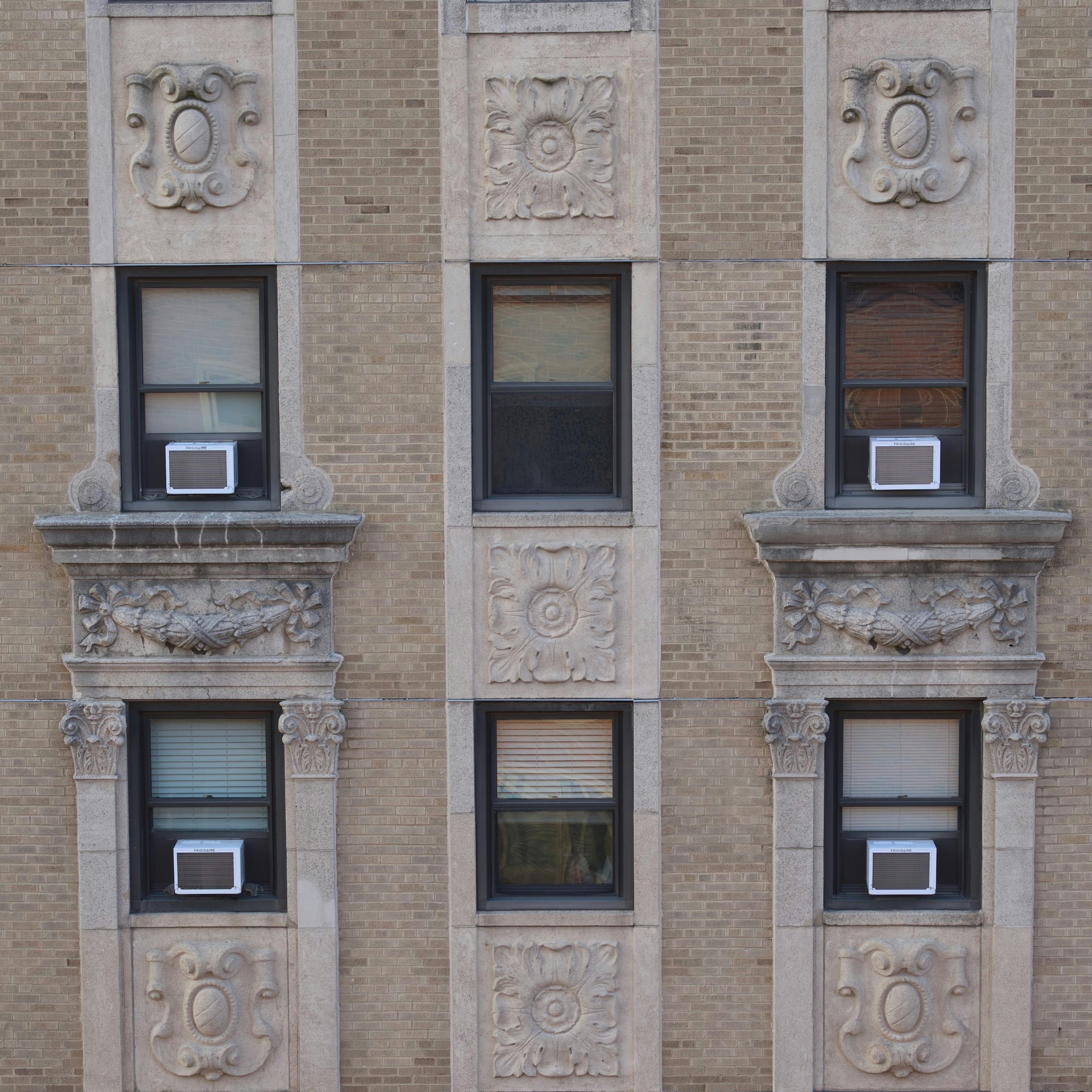 Symmetry in Stone: Three-Window Facade Framed by Rosettes and AC Units