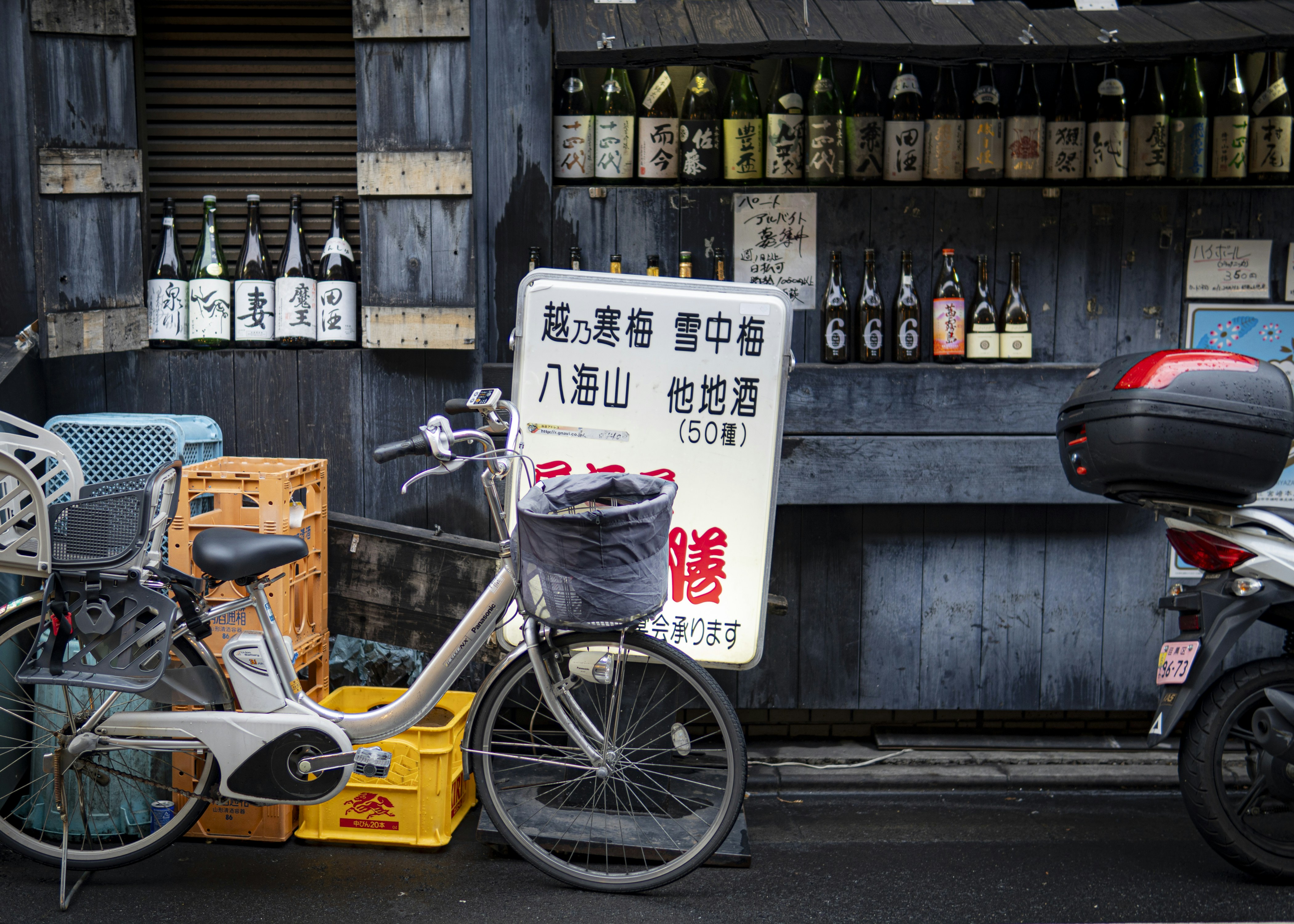 Bicycle by a bottle-lined facade under Japanese signage