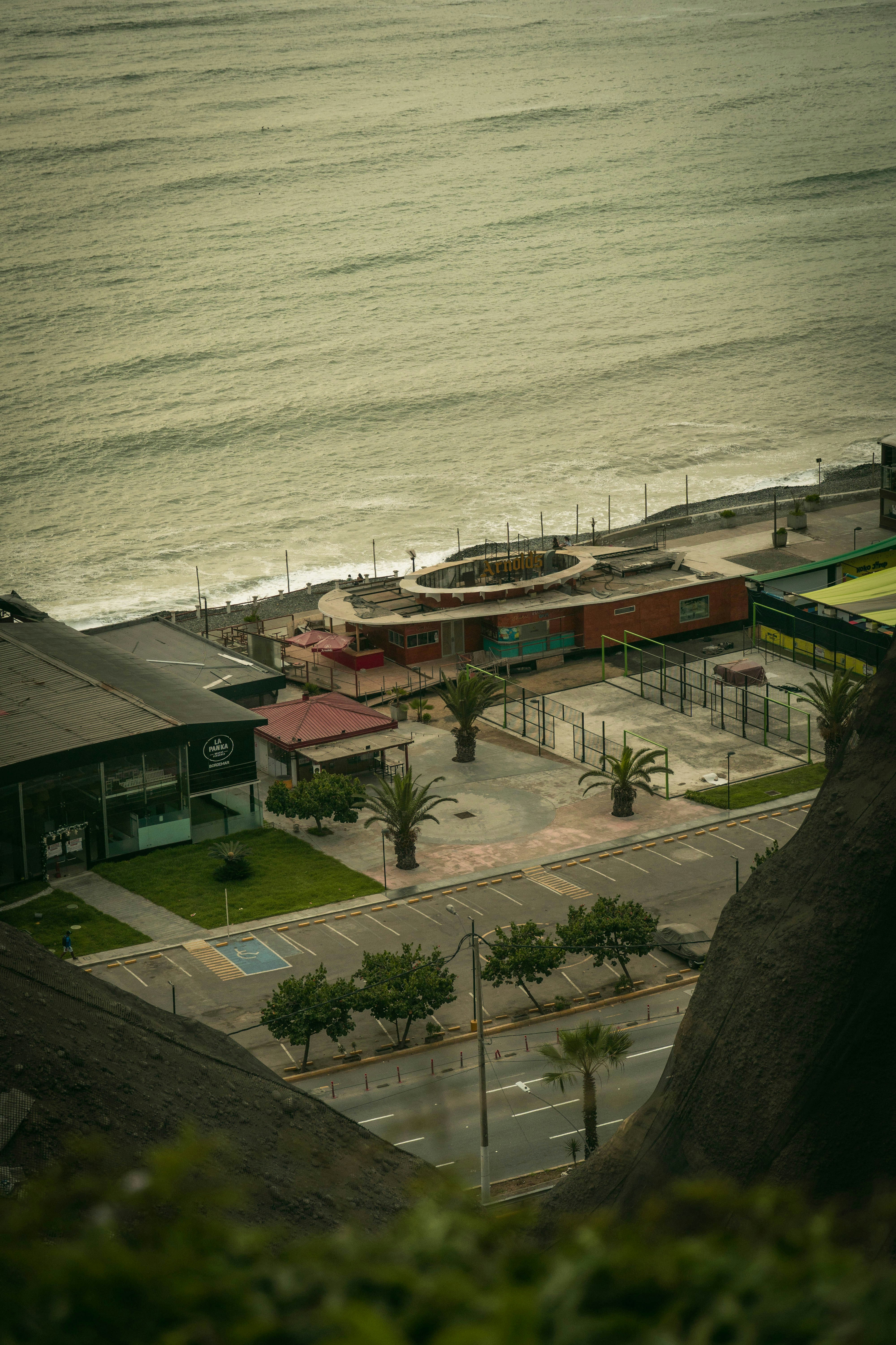 View of a coastal cityscape with a beachside promenade and gentle ocean waves.