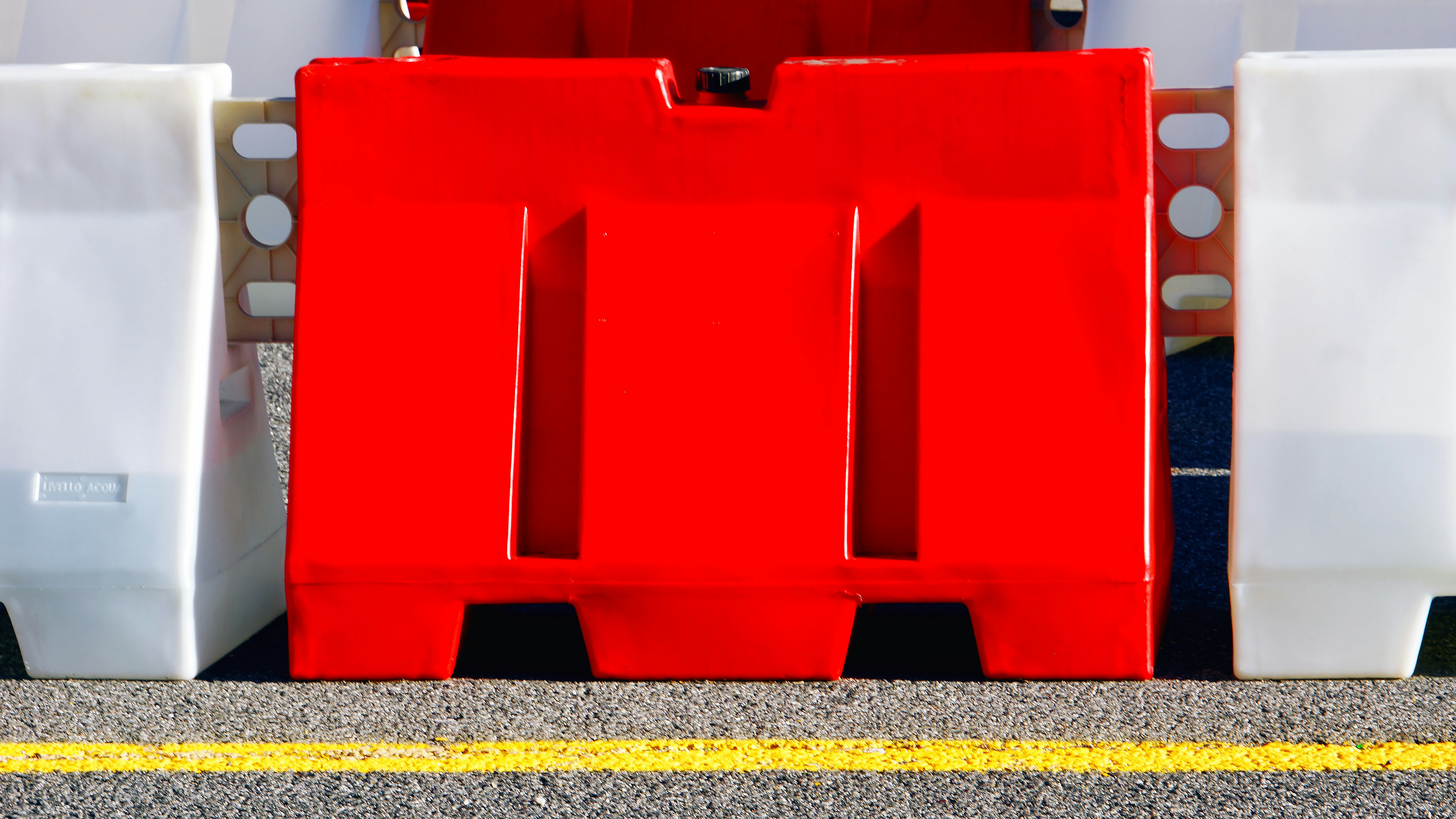 Crimson Gatekeeper: A Bold Red Barrier Anchoring a Sunlit Street