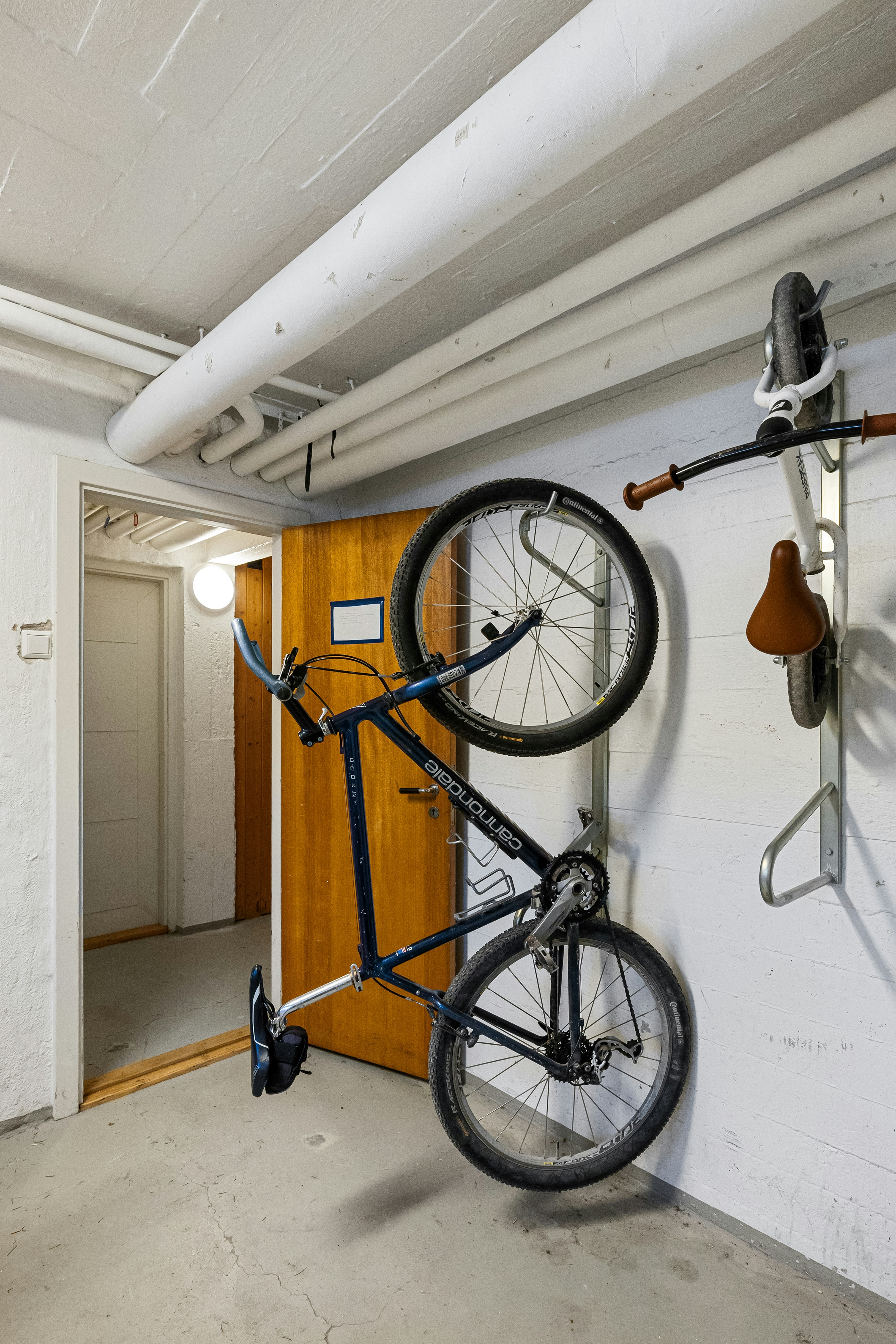 Suspended Blue Mountain Bike Anchored to a White Basement Wall