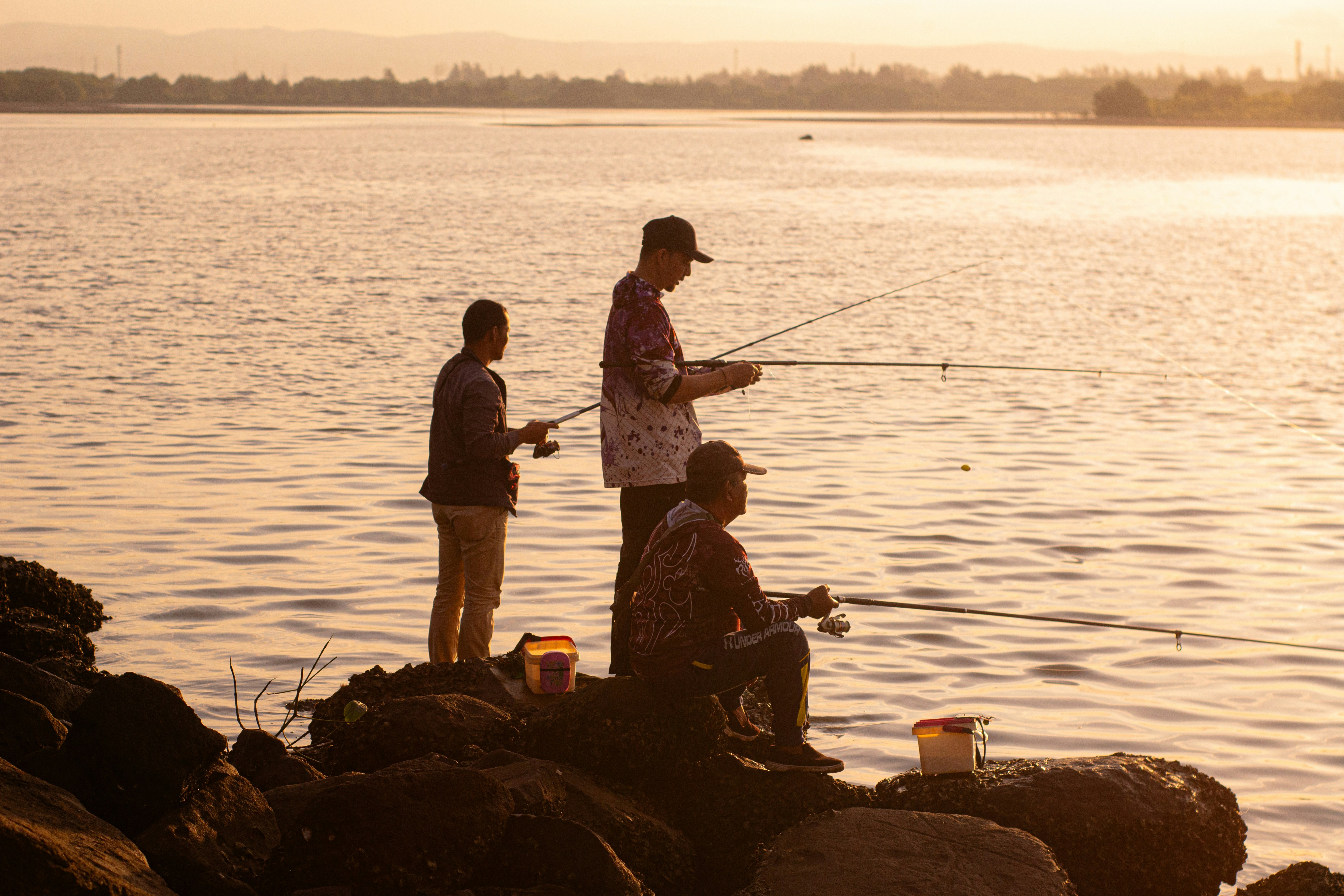 Rocks, Rods, and Dusk: Three Anglers at Water's Edge