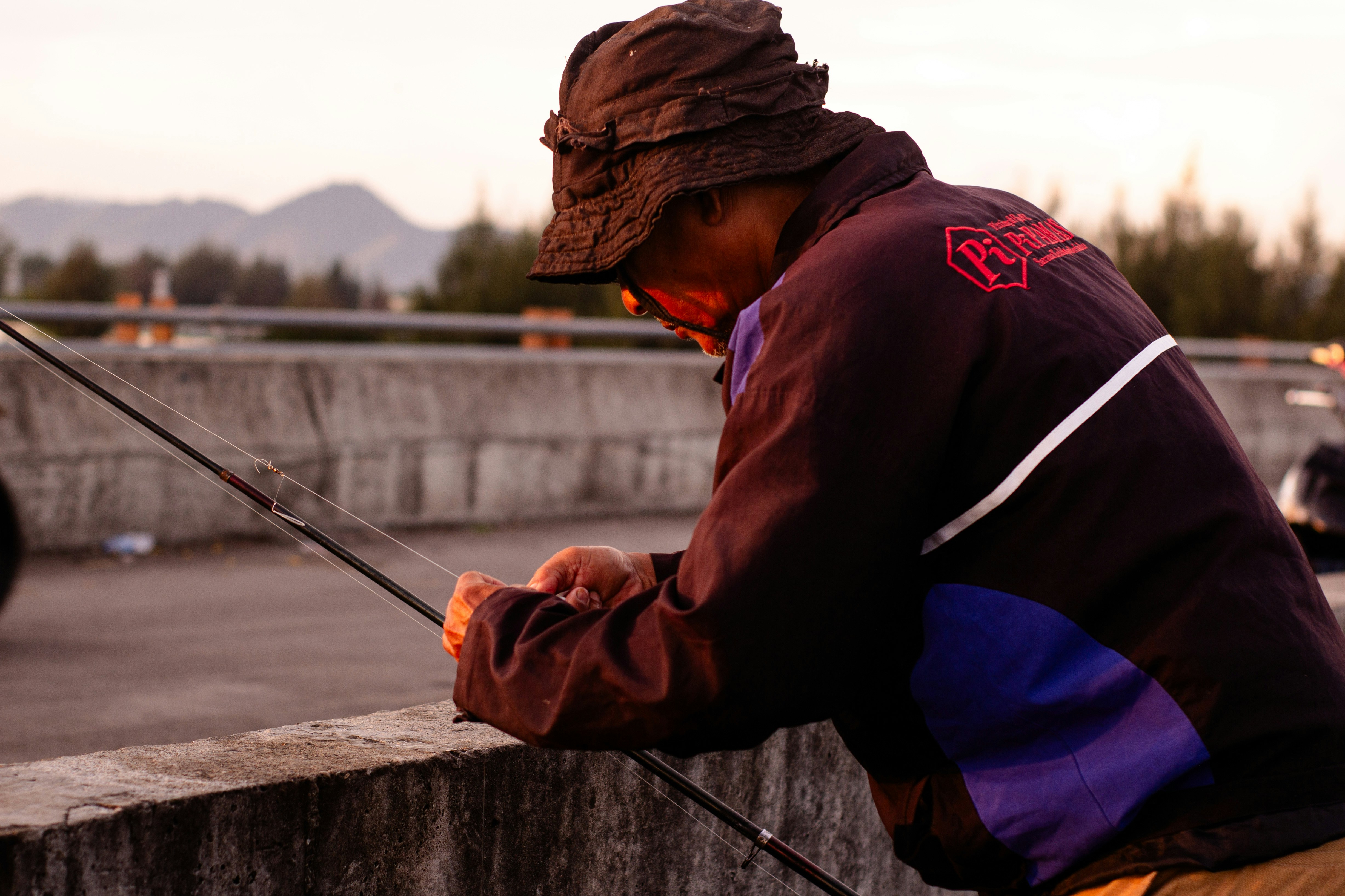 Dusk at the Concrete Railing: An Angler Tends the Line