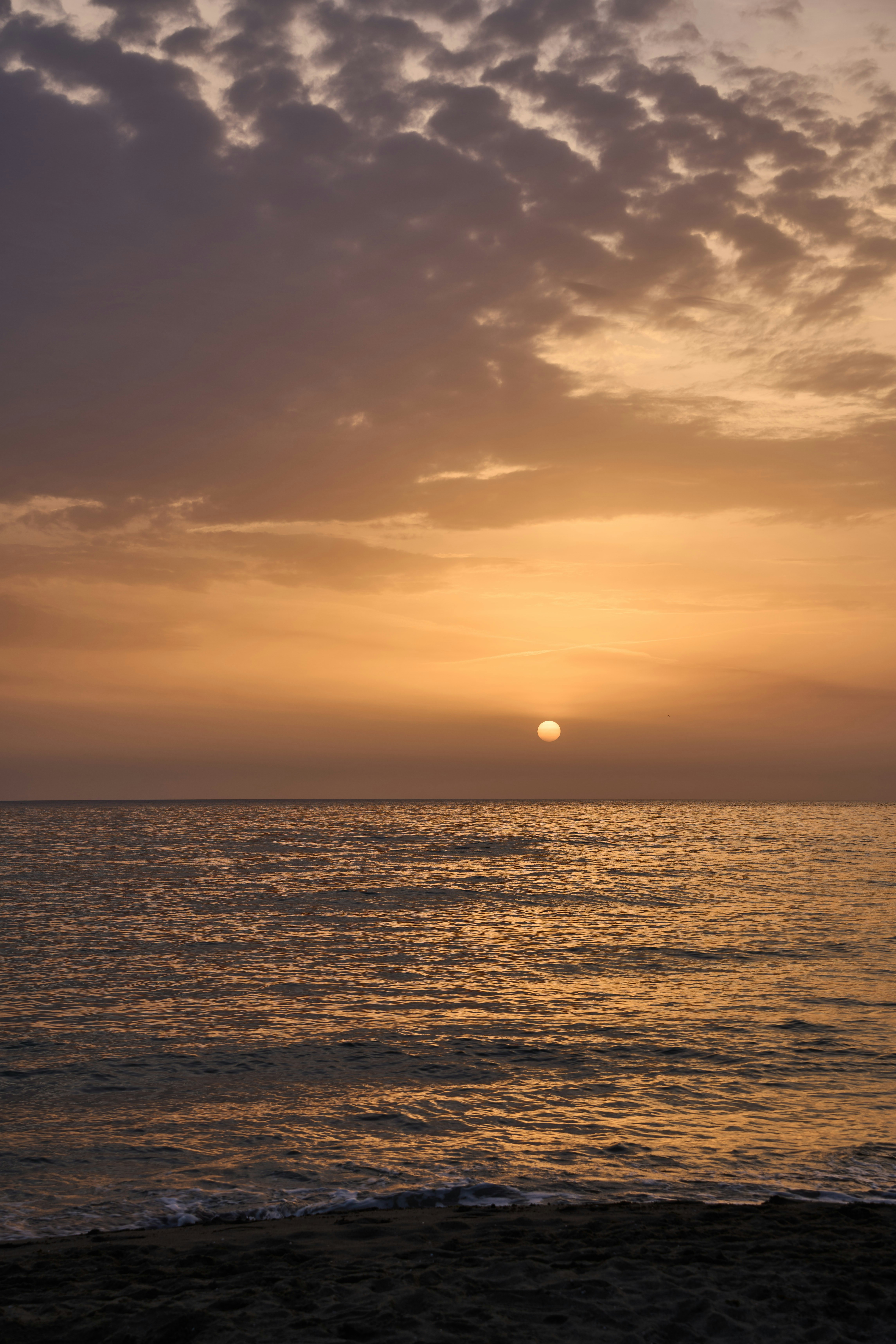 The sun is setting over the ocean on a cloudy day photo – Free Nature ...