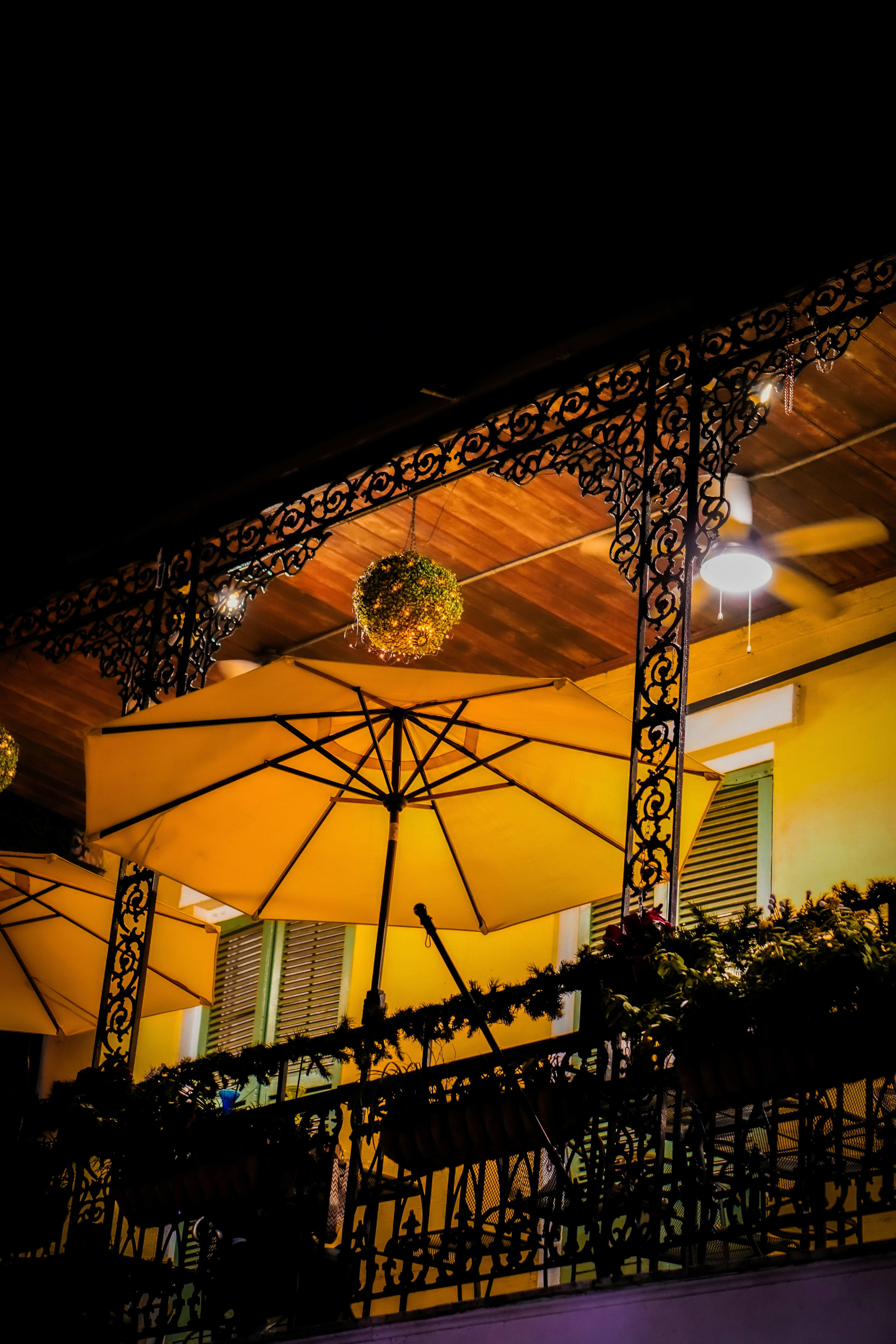 A yellow building with a balcony and umbrellas lit up at night photo ...