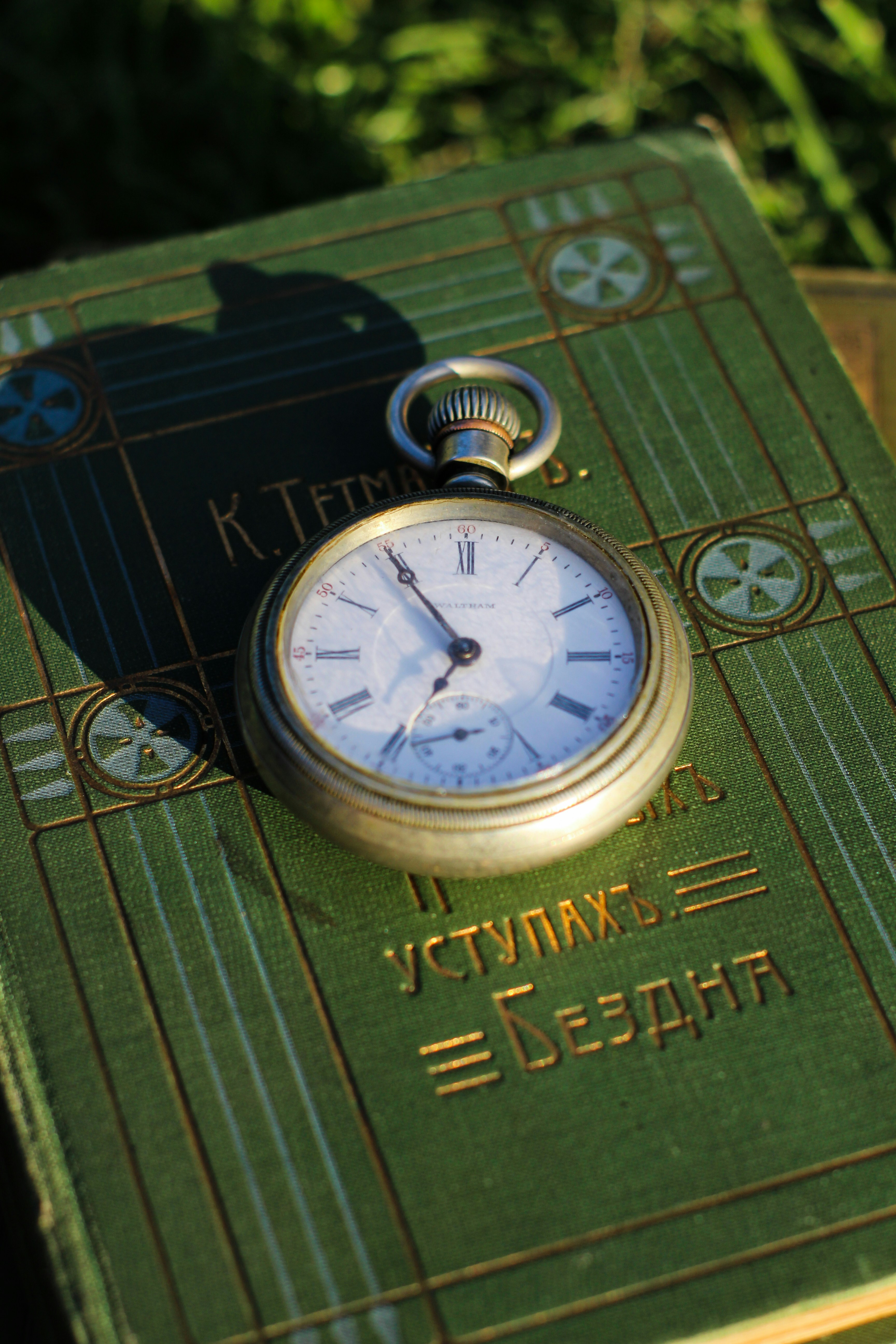 Ticking in the Margins: A Brass Pocket Watch on a Green Embossed Tome