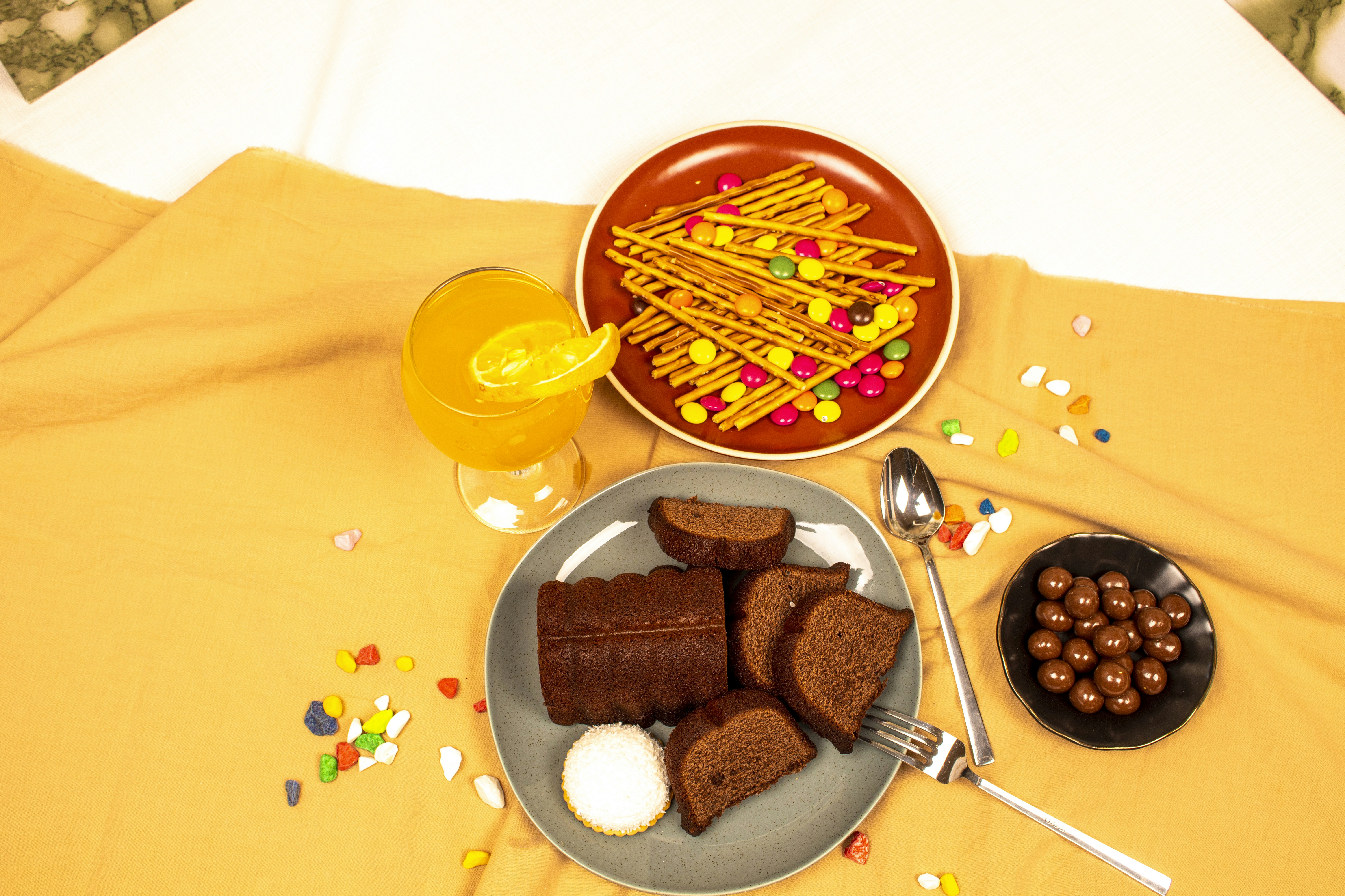 Sunlit Dessert Mosaic: Brownies, Sprinkles, and Citrus on Yellow Linen