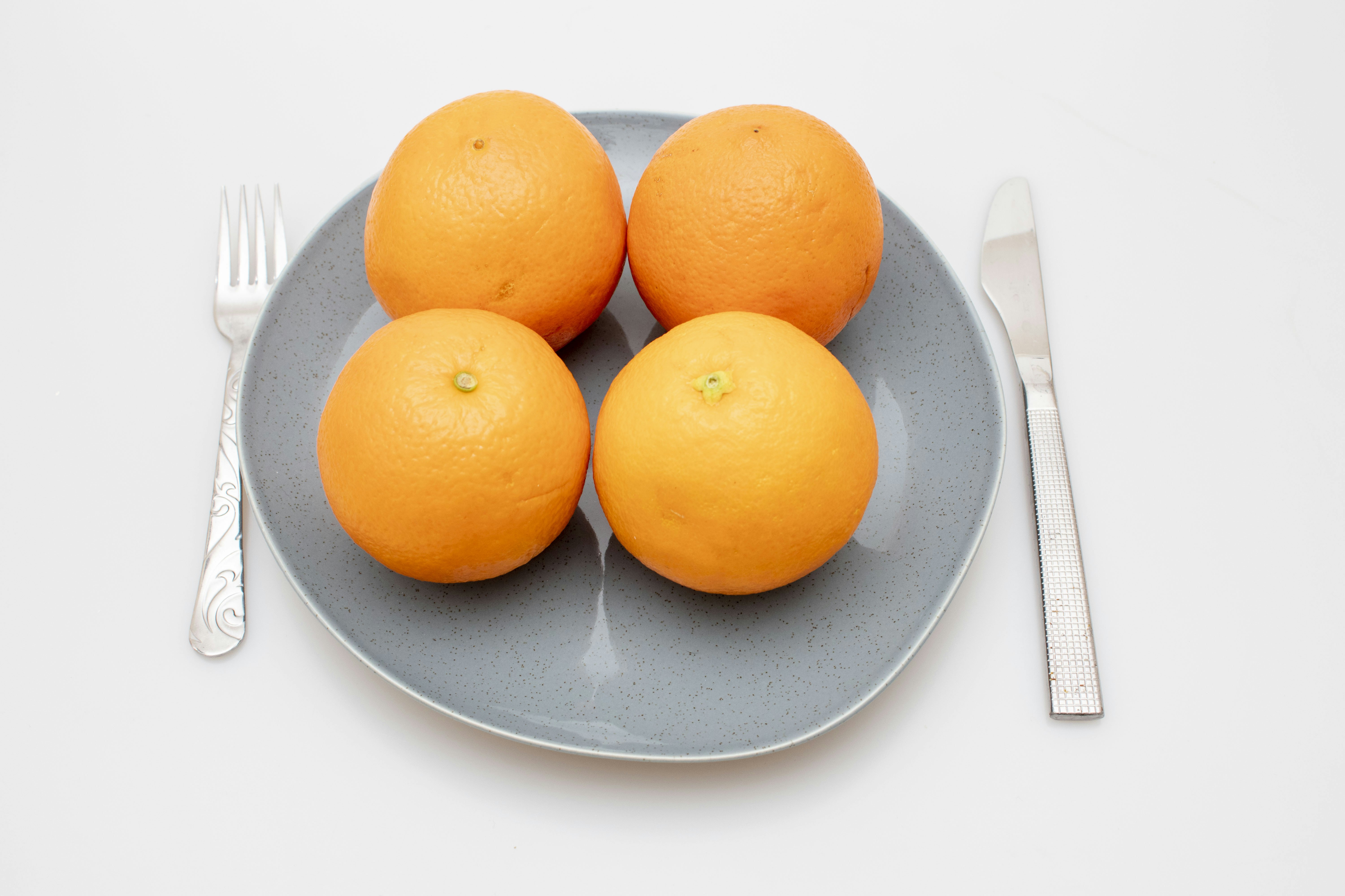 Four oranges on a plate with a fork and knife photo – Free Citrus fruit ...