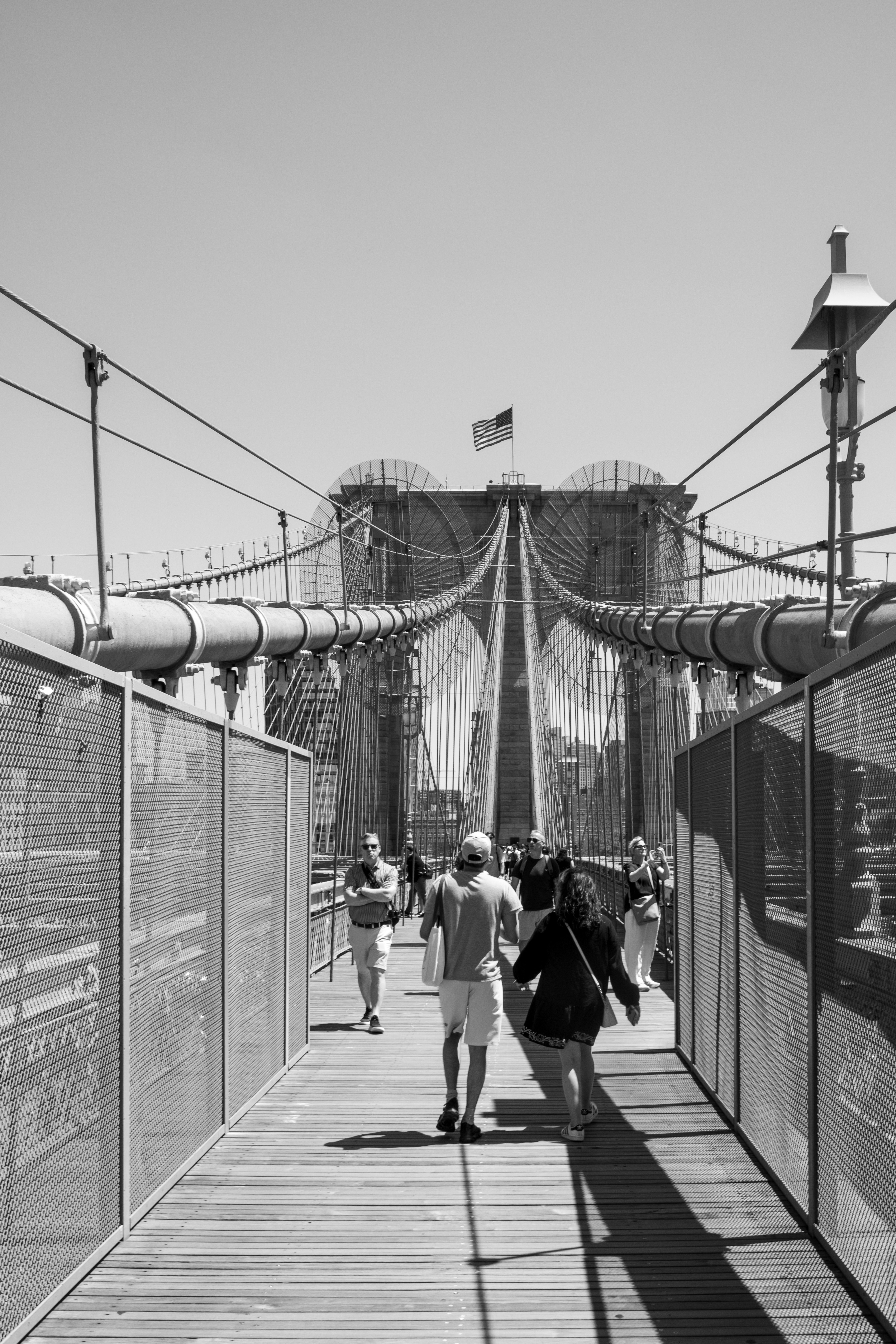 The Brooklyn Bridge, an iconic symbol of New York City, connects Manhattan and Brooklyn, spanning the East River. Completed in 1883 after 14 years of construction, it was the world's first steel-wire suspension bridge, with a main span of 1,595 feet (486m). The project cost $15 million (about $400 million today) and involved over 600 workers, with at least 20 fatalities, including the original designer, John A. Roebling.