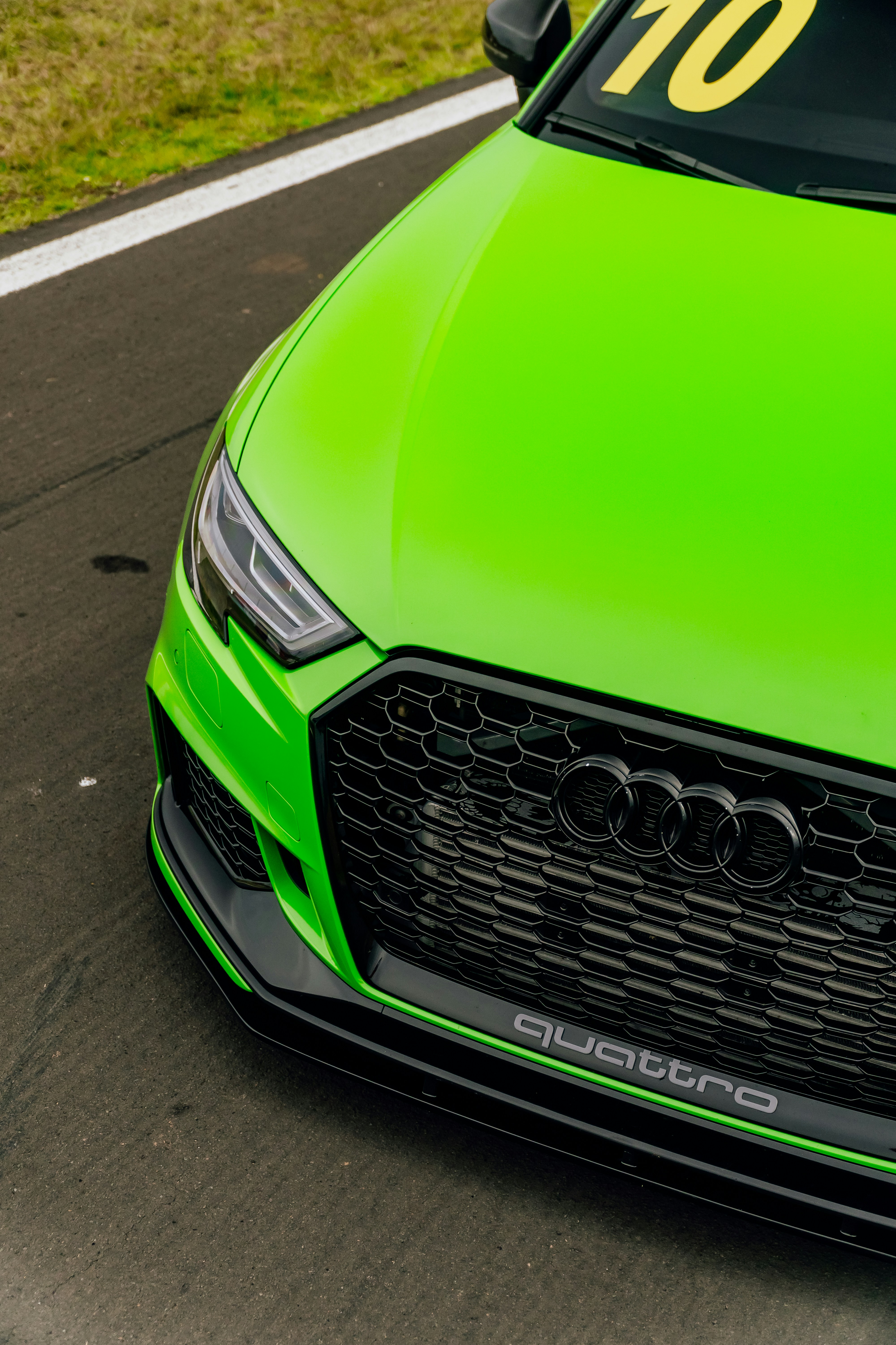 A green car driving down a road next to a lush green field photo – Free ...