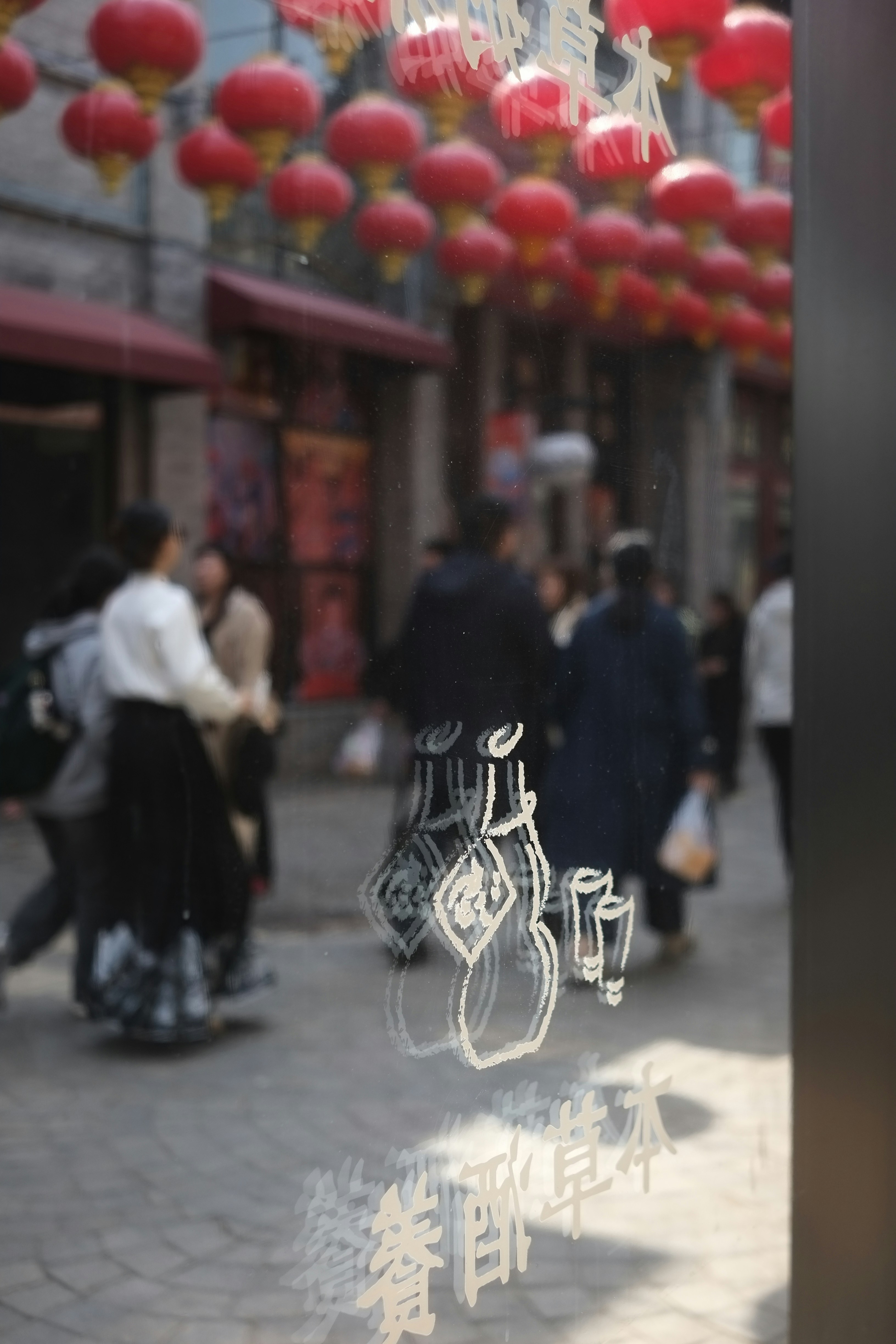 Reflections of Lanterns and Passersby on a Glass Door