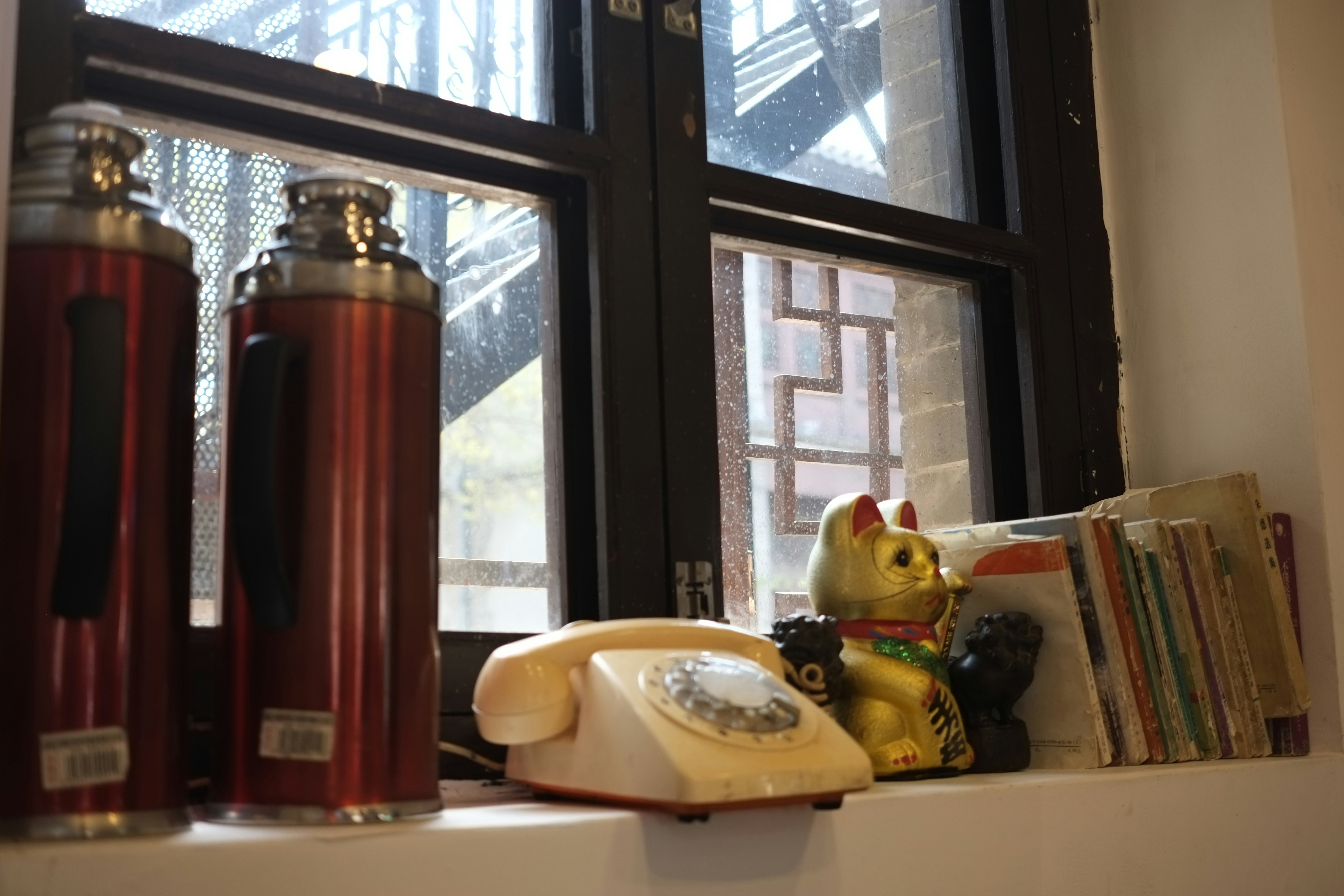 Sunlit Windowsill: The Maneki-neko Among Vintage Phones and Books