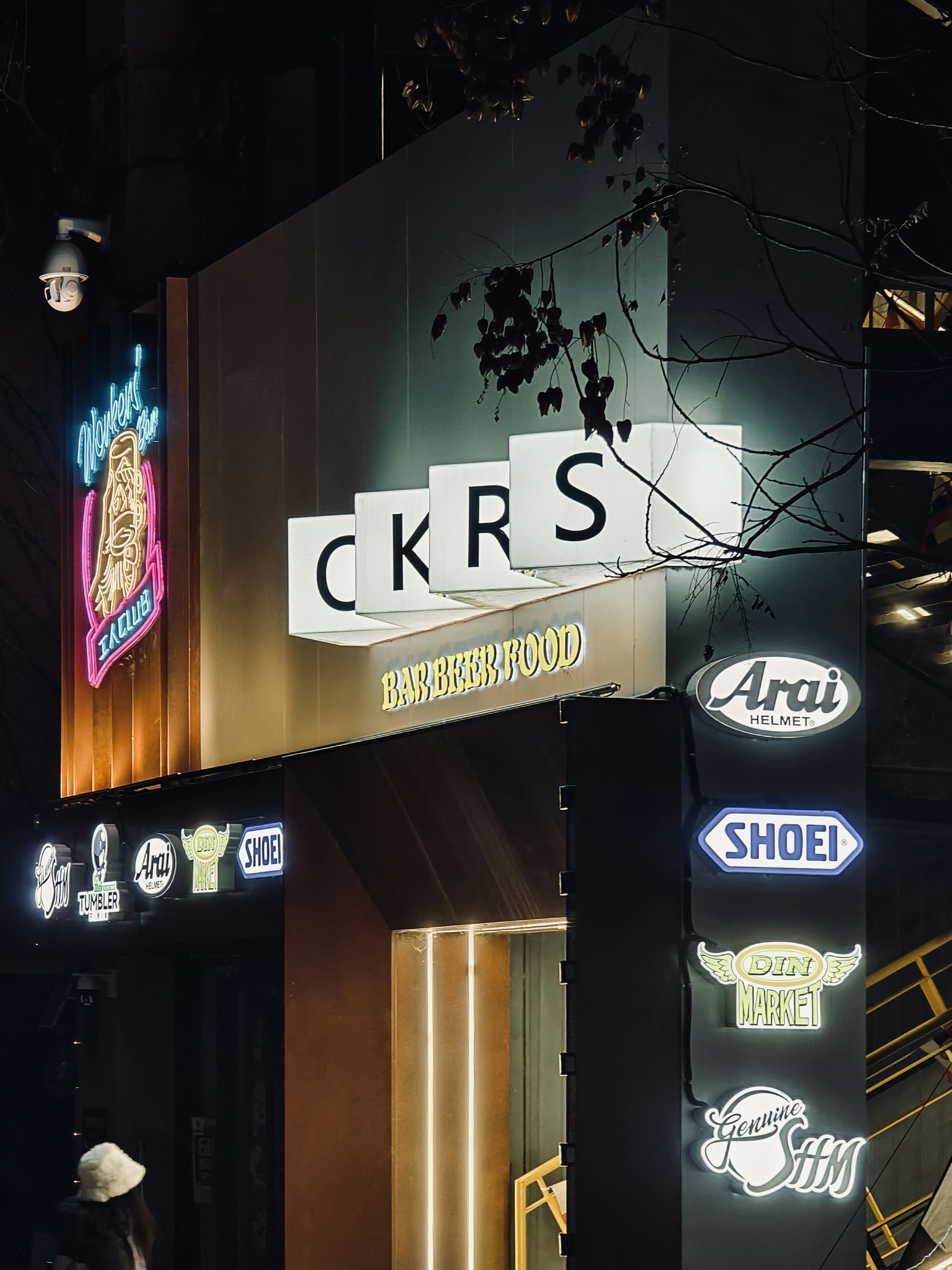 Nighttime storefront photograph with neon signage and CKRS logo blocks, plus brand logos along the lit facade.