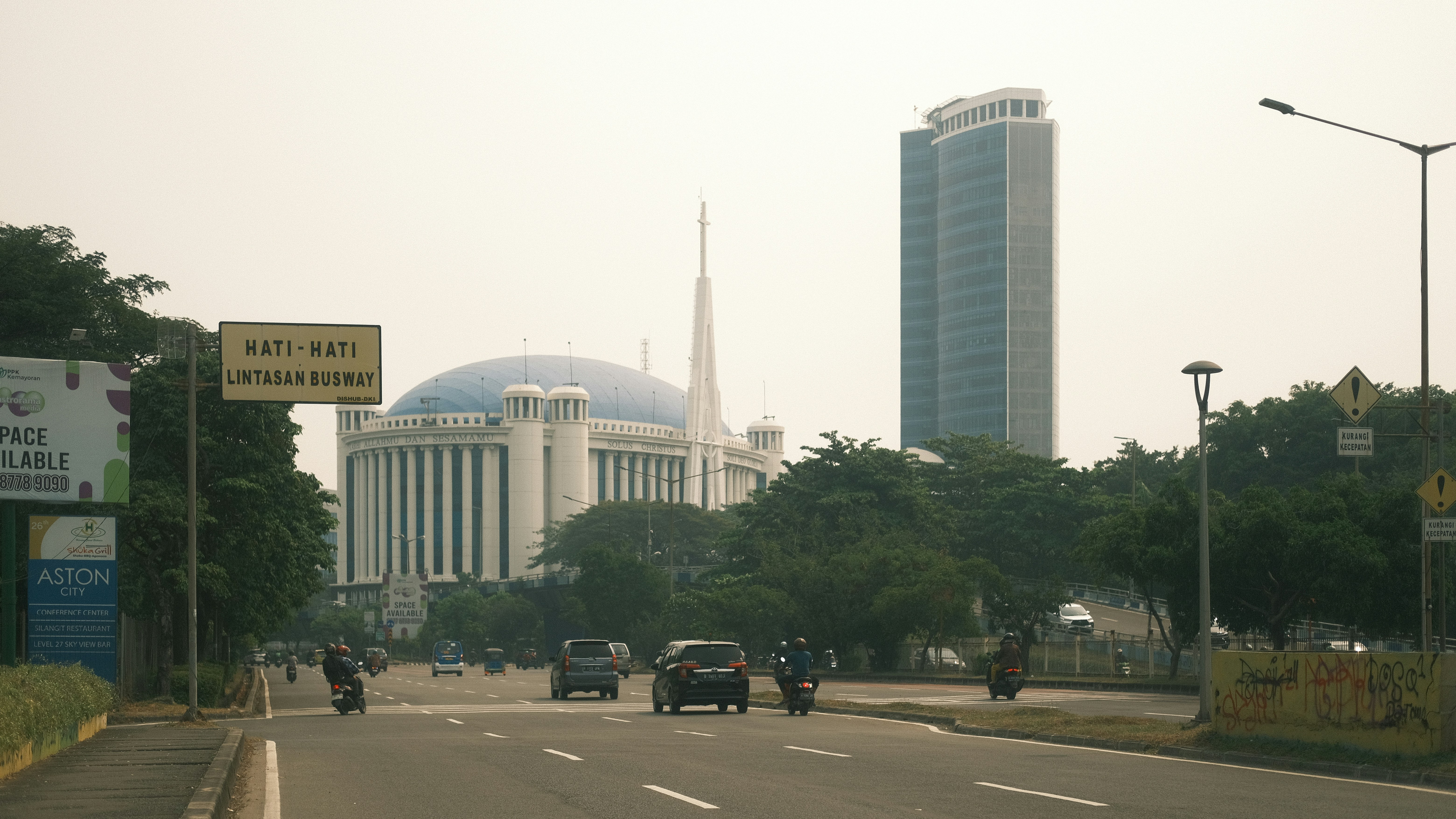 A bustling street scene showcasing a blend of modern skyscrapers and traditional architecture under a hazy sky.