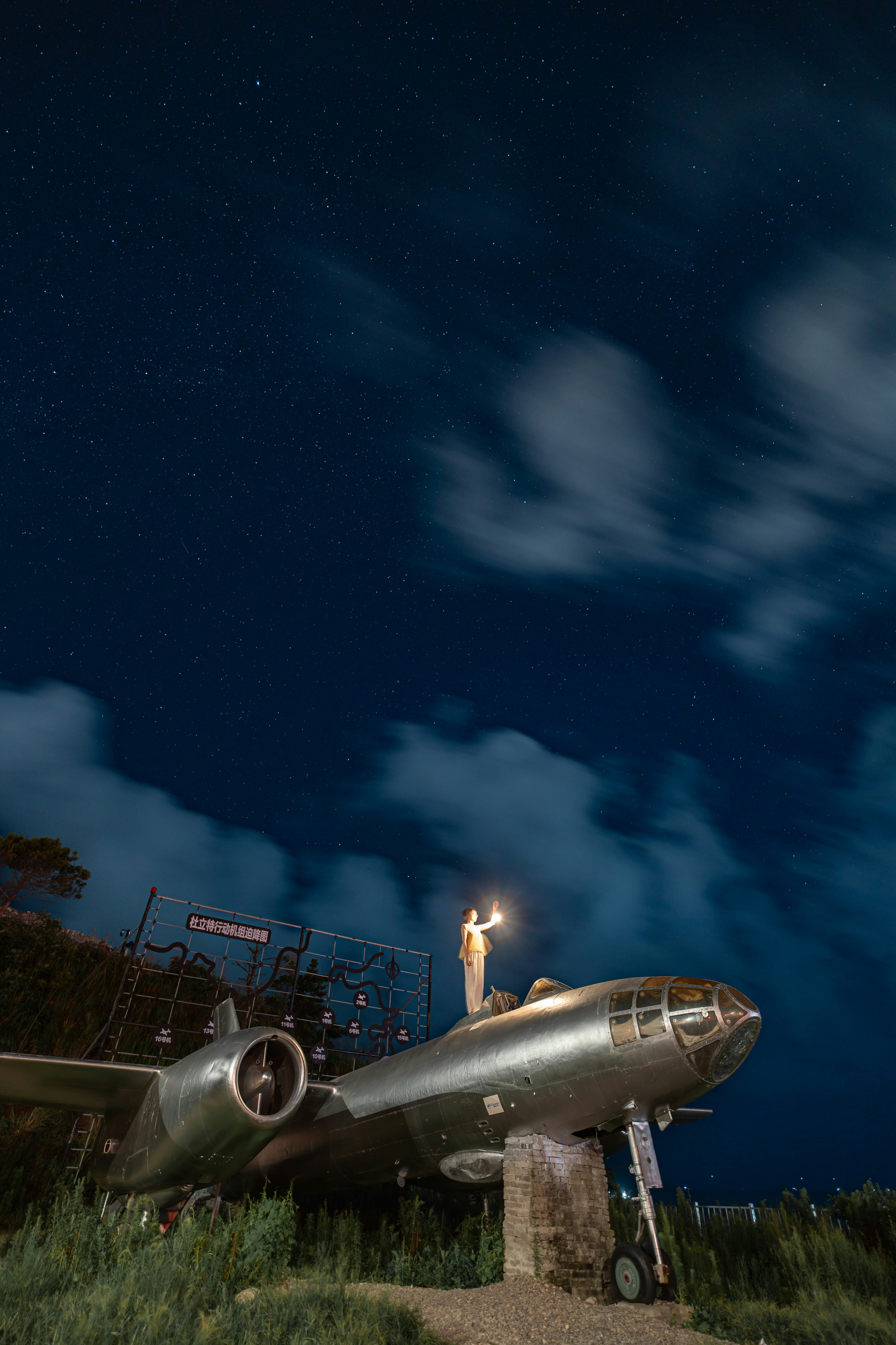 Starlit Sentinel: A figure atop a vintage bomber aglow under a velvet night sky