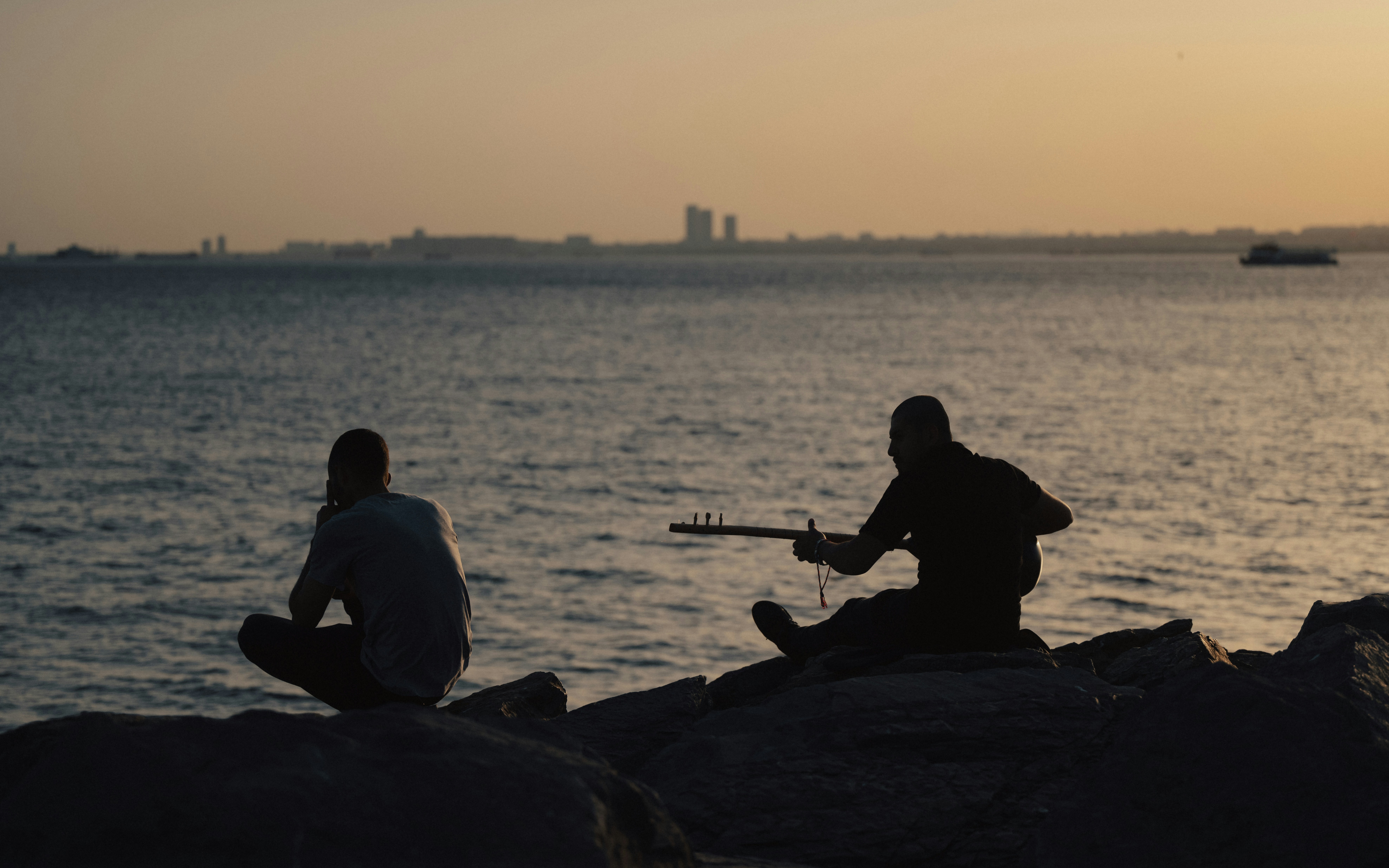 Dusk Silhouette on the Rocky Seashore: a rifle-wielding figure against the calm horizon