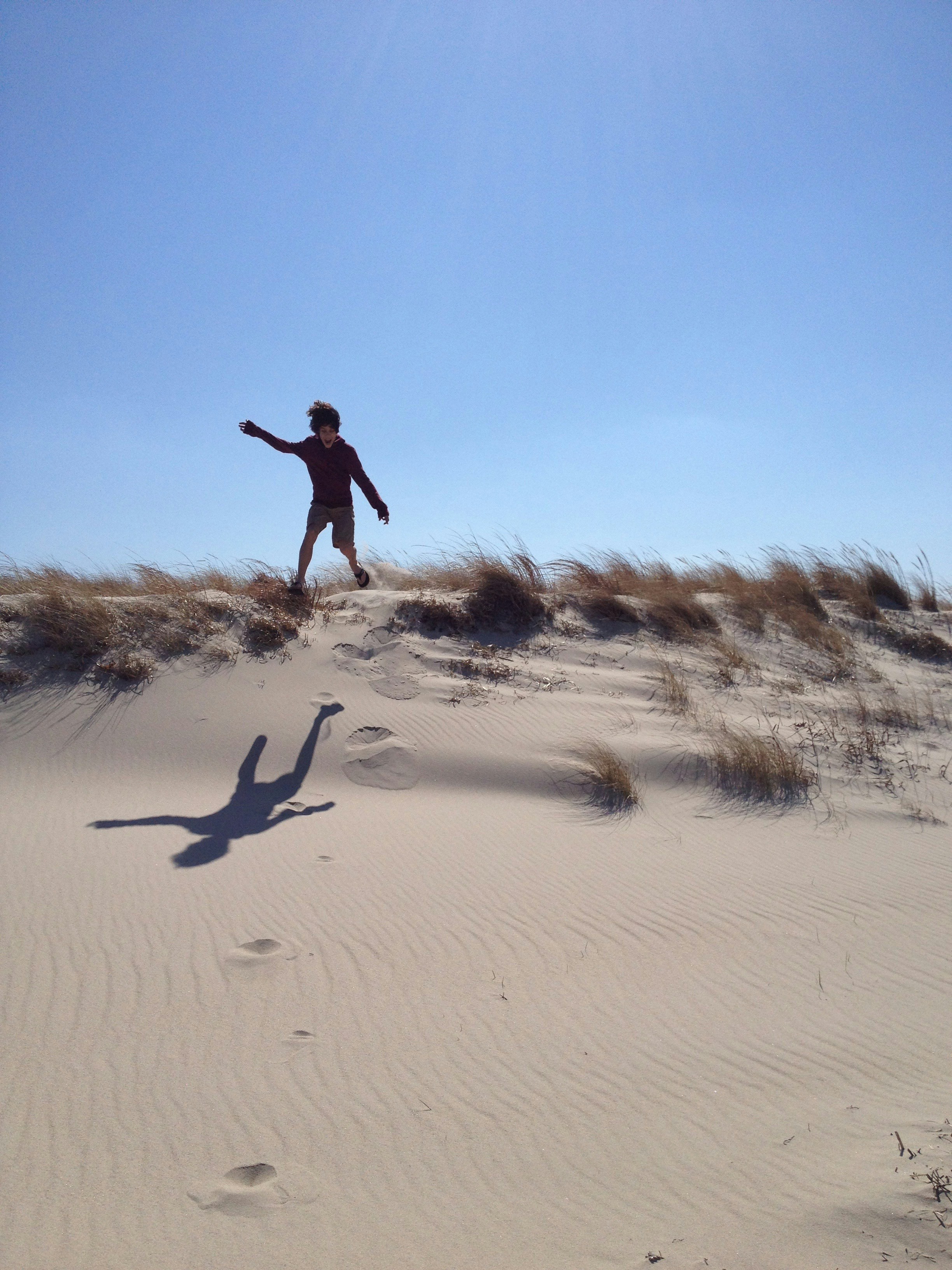 Dune Crest Leap: A lone figure suspended against a cobalt sky