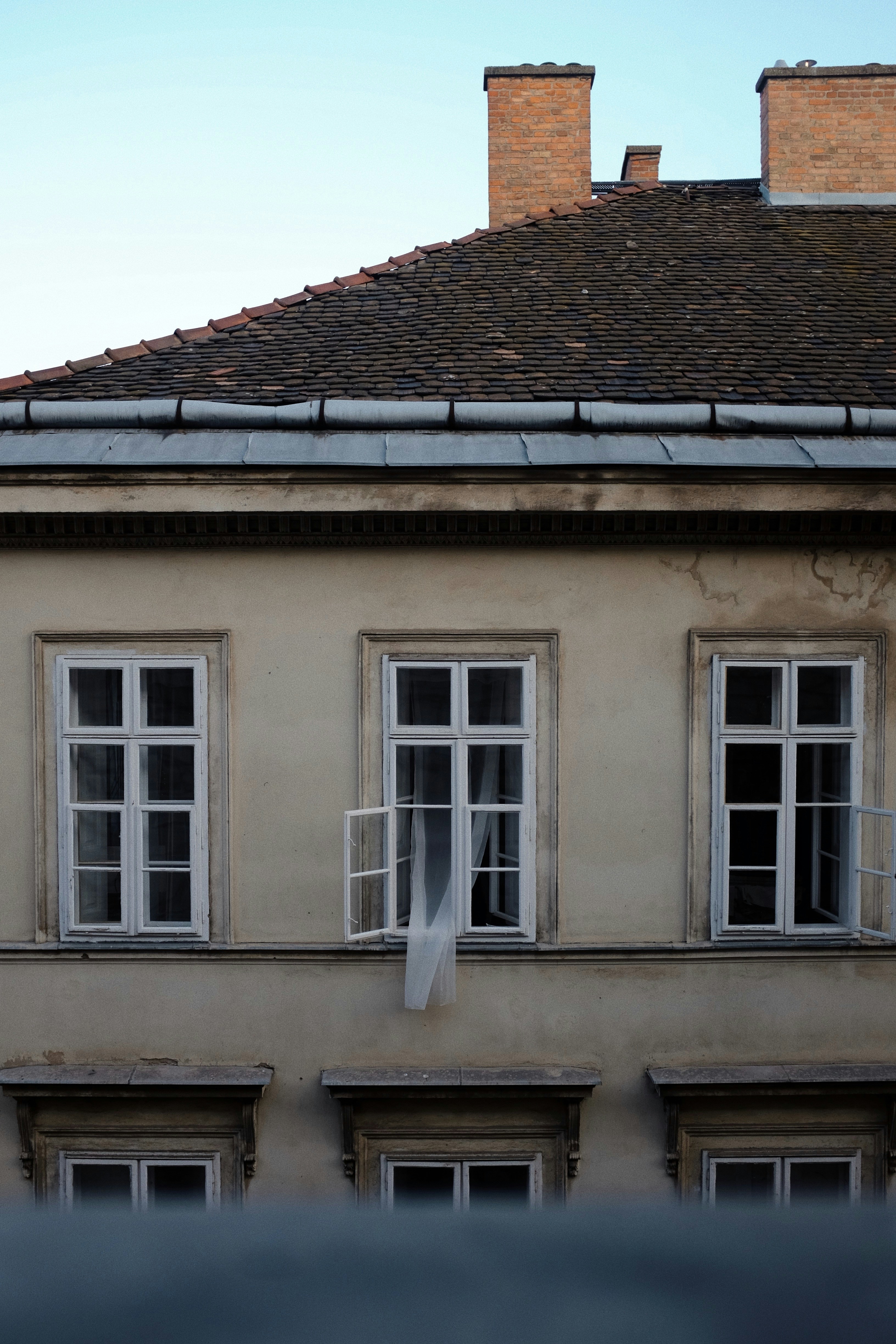 Curtain Between Windows: A Pale Facade's Quiet Breeze