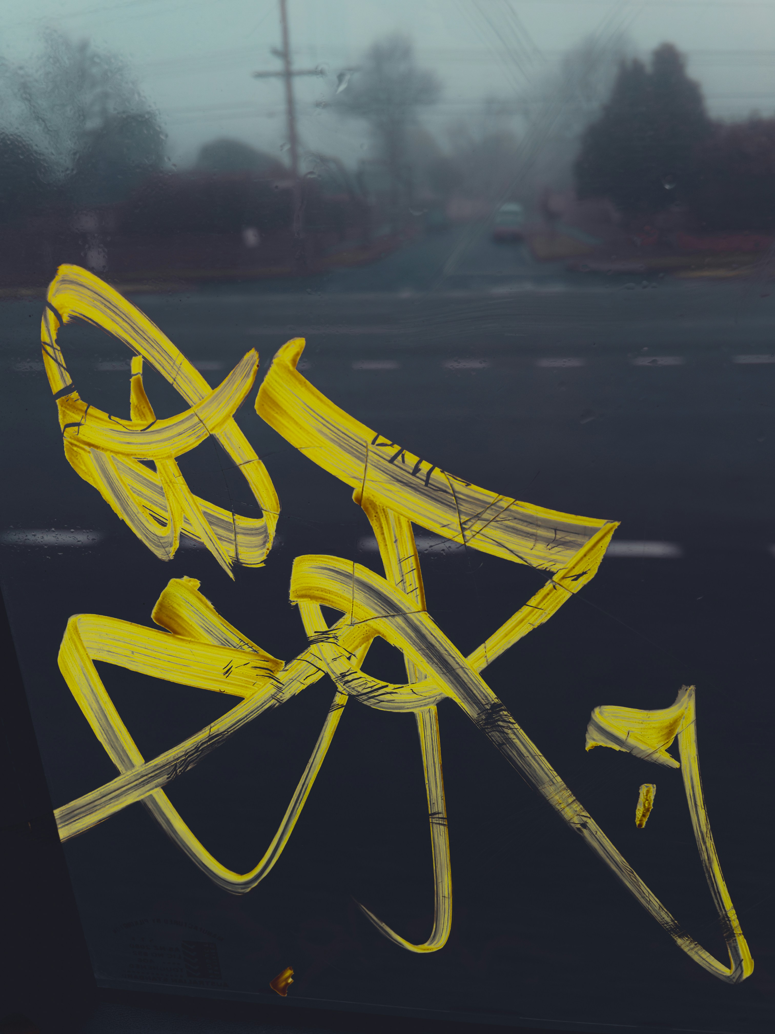 Yellow graffiti loops on glass with a hazy street receding behind