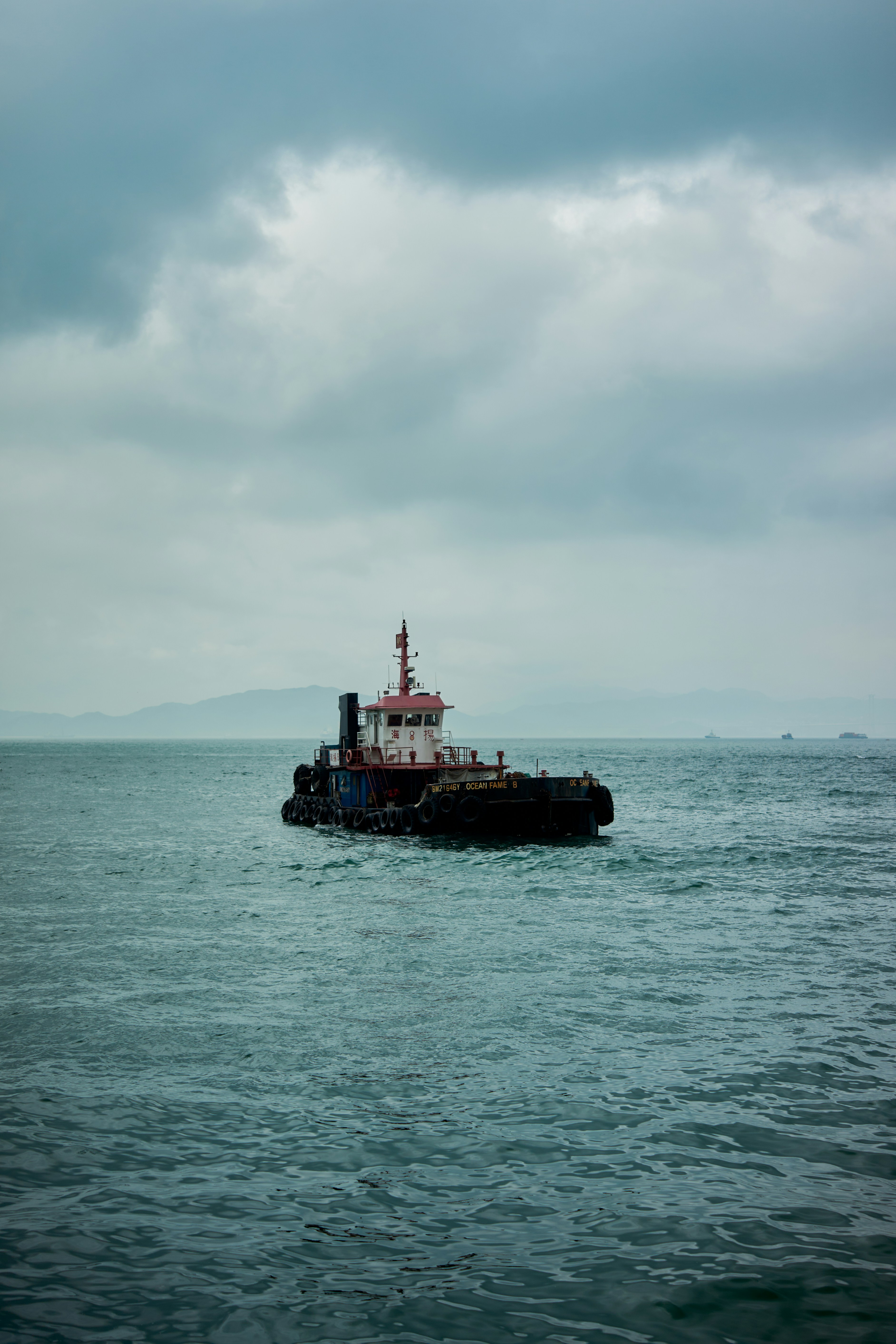 Harbor Drifter: A Lone Tugboat Between Sea Calm and Overcast Sky