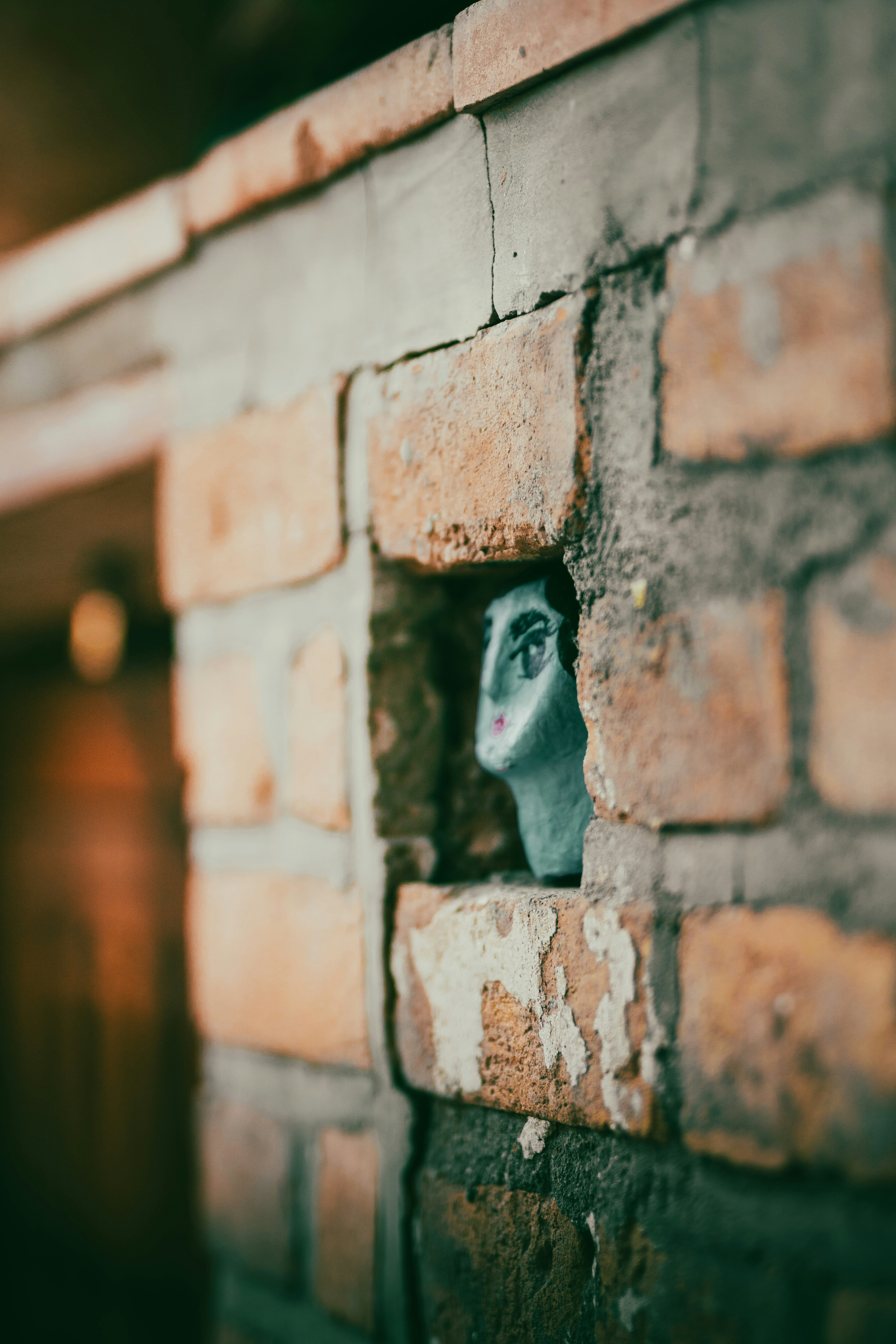 A brick wall with a blue face sticking out of it photo – Free Building ...
