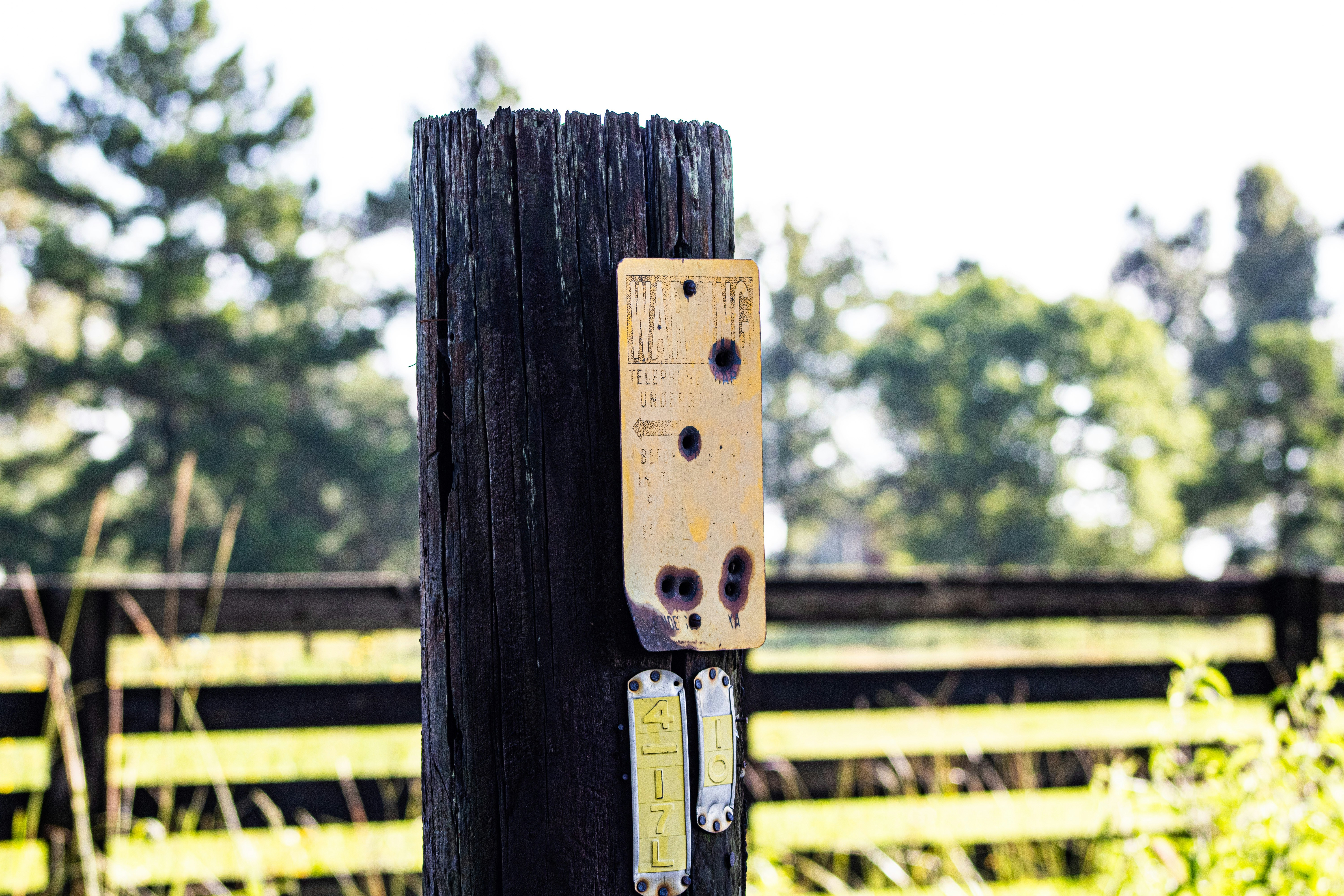 Weathered post with a yellow utility box in a sunlit rural setting