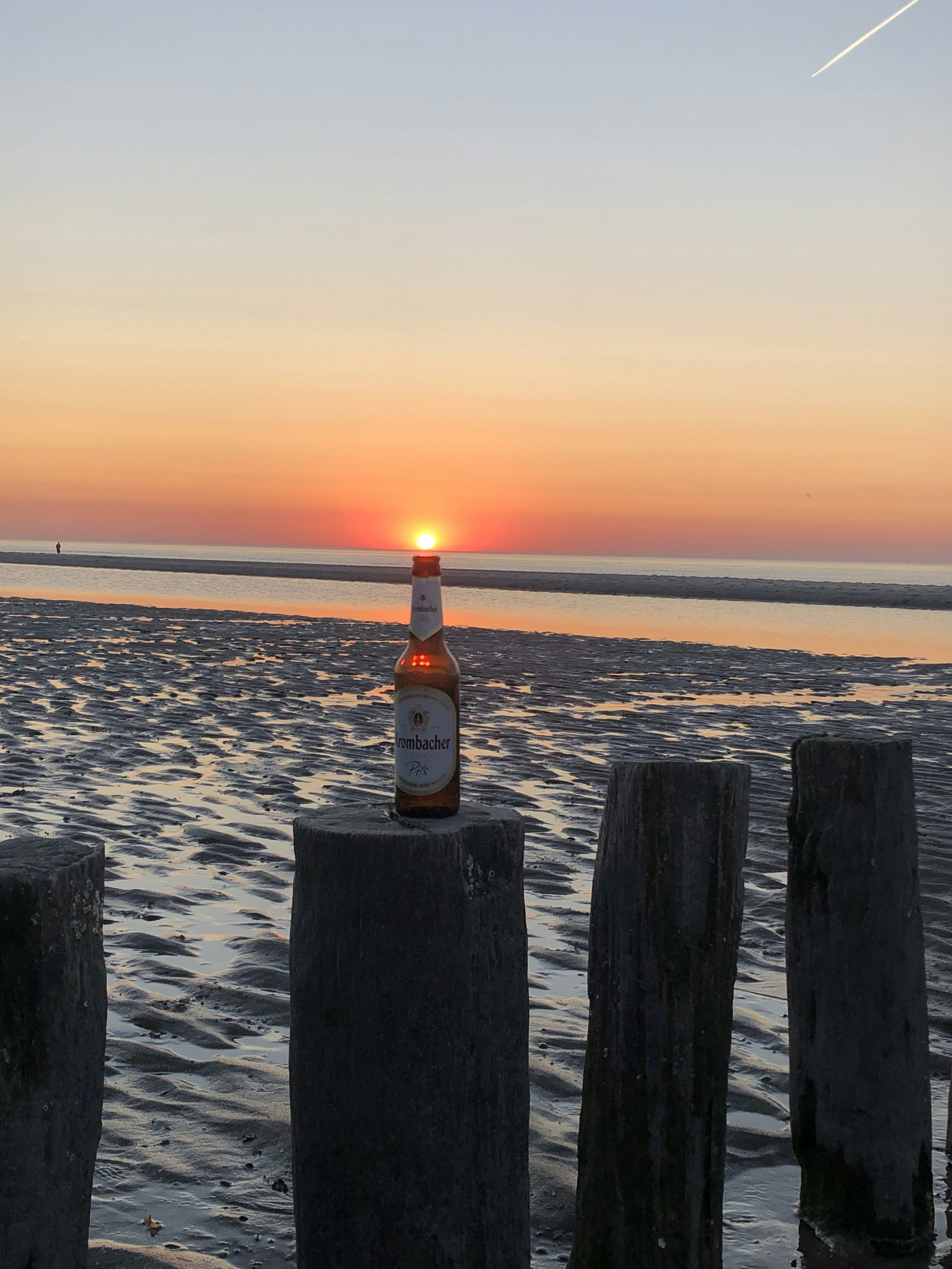 Amber Sunset Perch: A Beer Bottle on Weathered Piers at Dusk