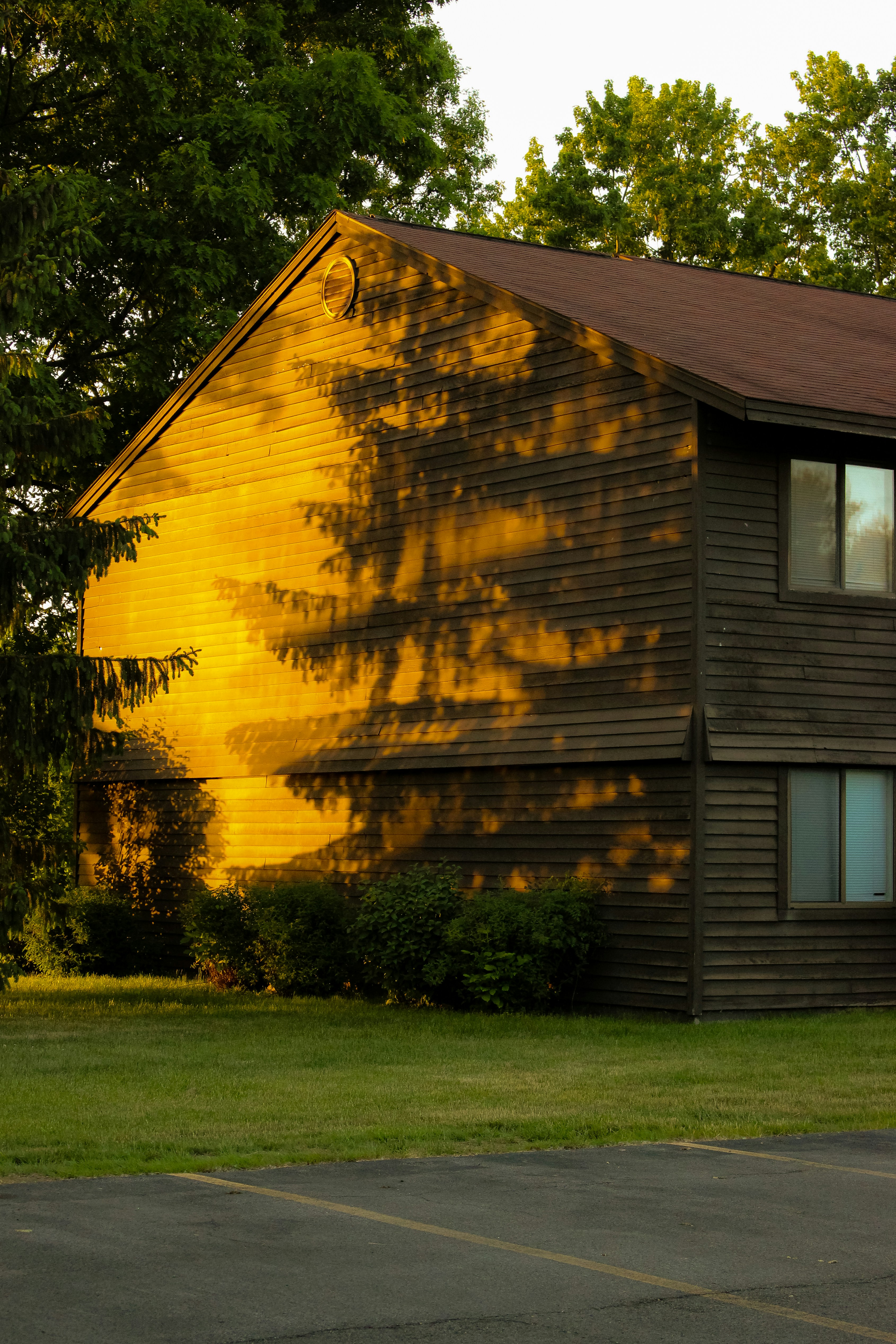 A large brown house sitting next to a lush green forest photo – Free ...