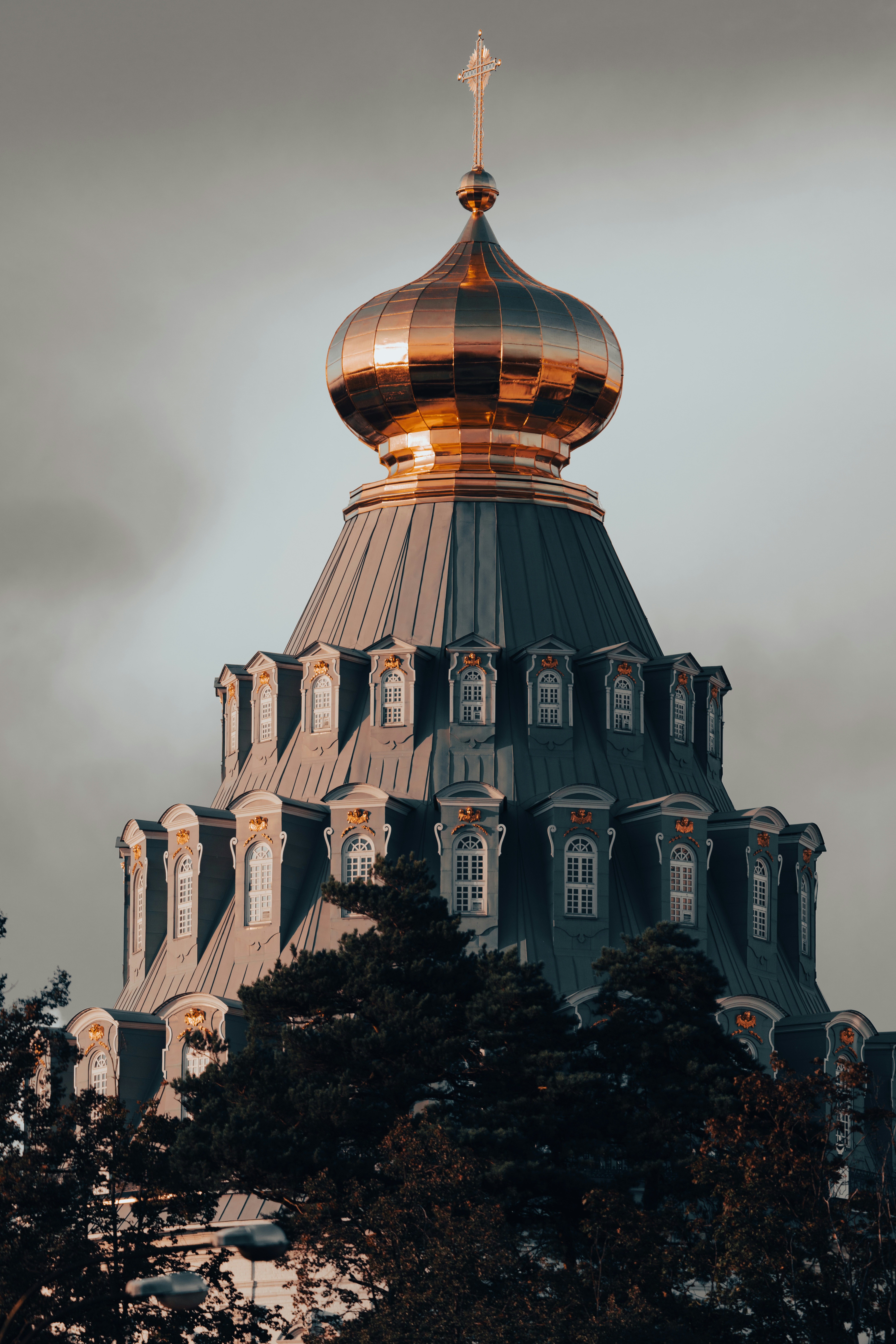 Copper Crown Over a Tulip-Domed Cathedral Framed by Pines at Dusk
