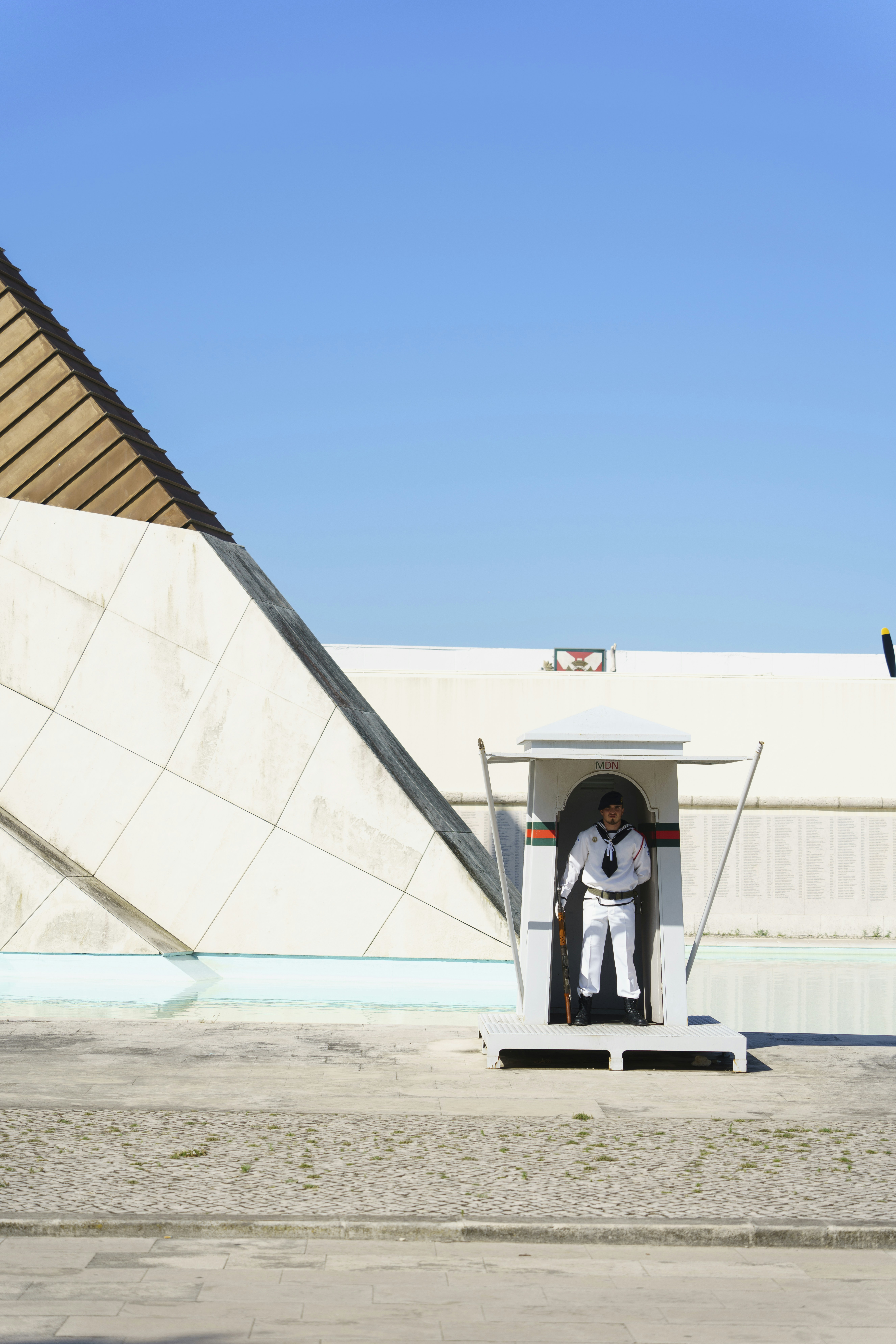 Sentry at the White Prism: a lone guard amid angular architecture under a cerulean sky