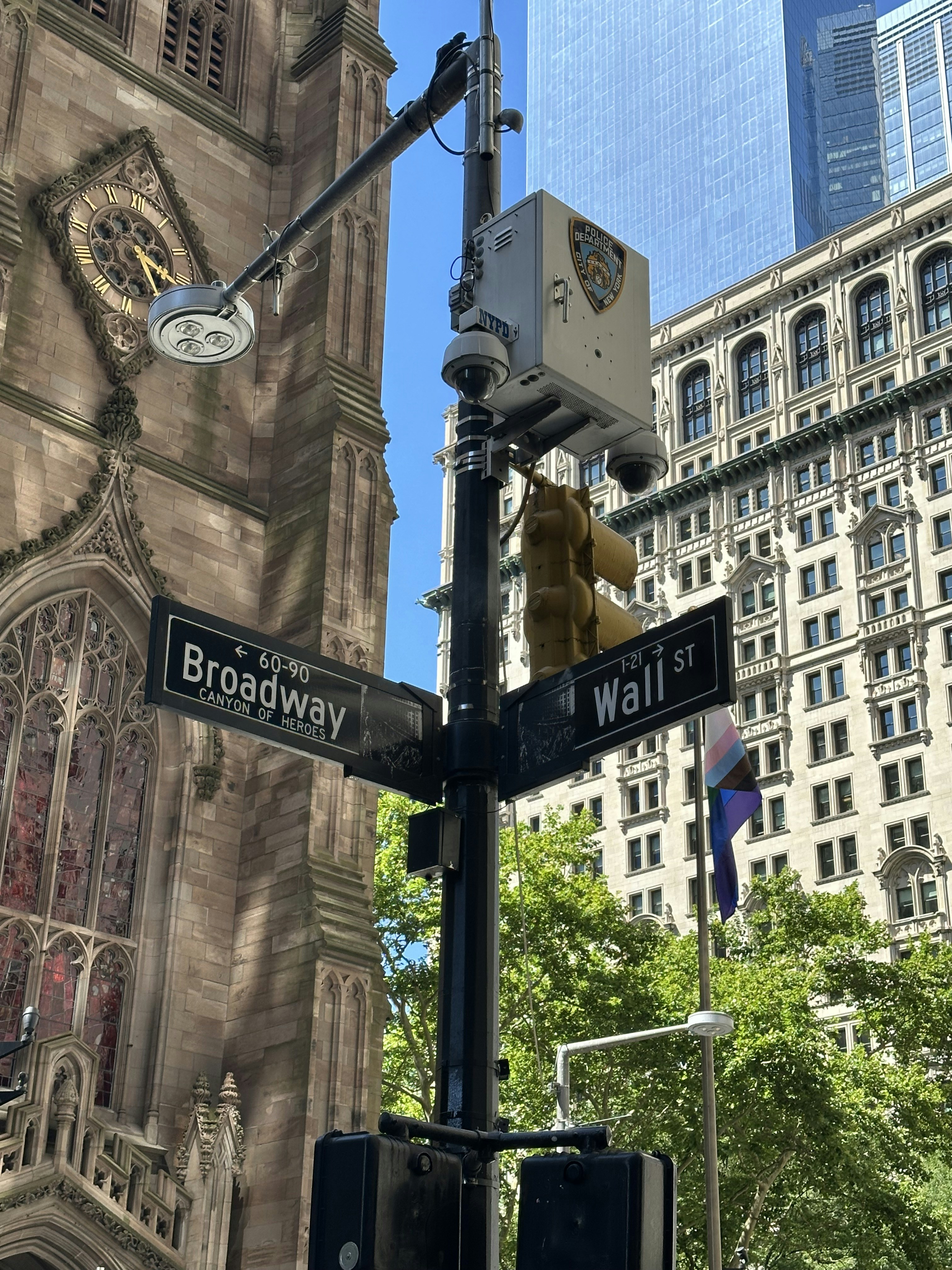 Broadway and Wall Street signs hang at the corner beside Trinity Church in the Financial District, New York City.