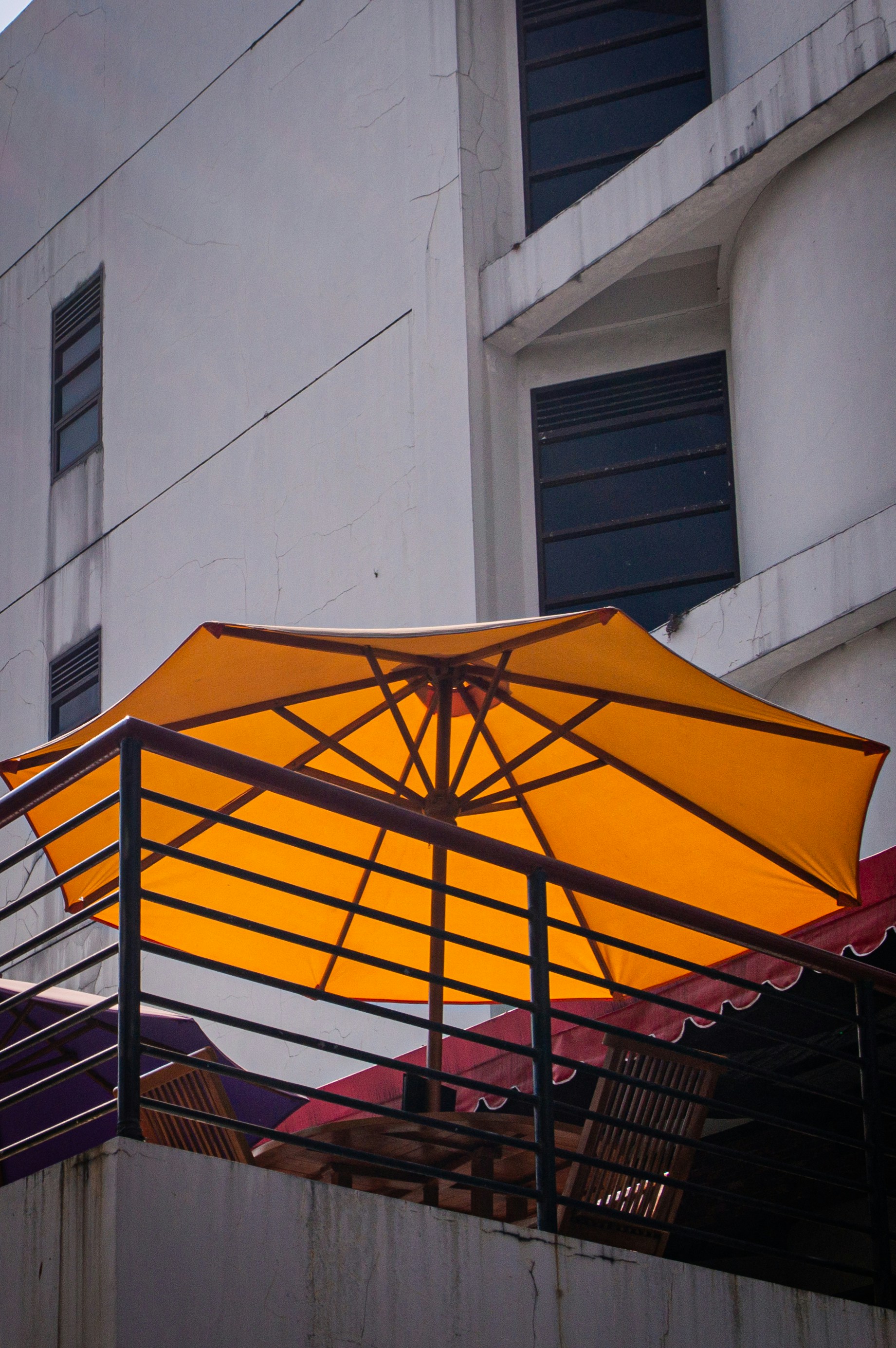 A yellow umbrella sitting on top of a metal railing photo – Free ...